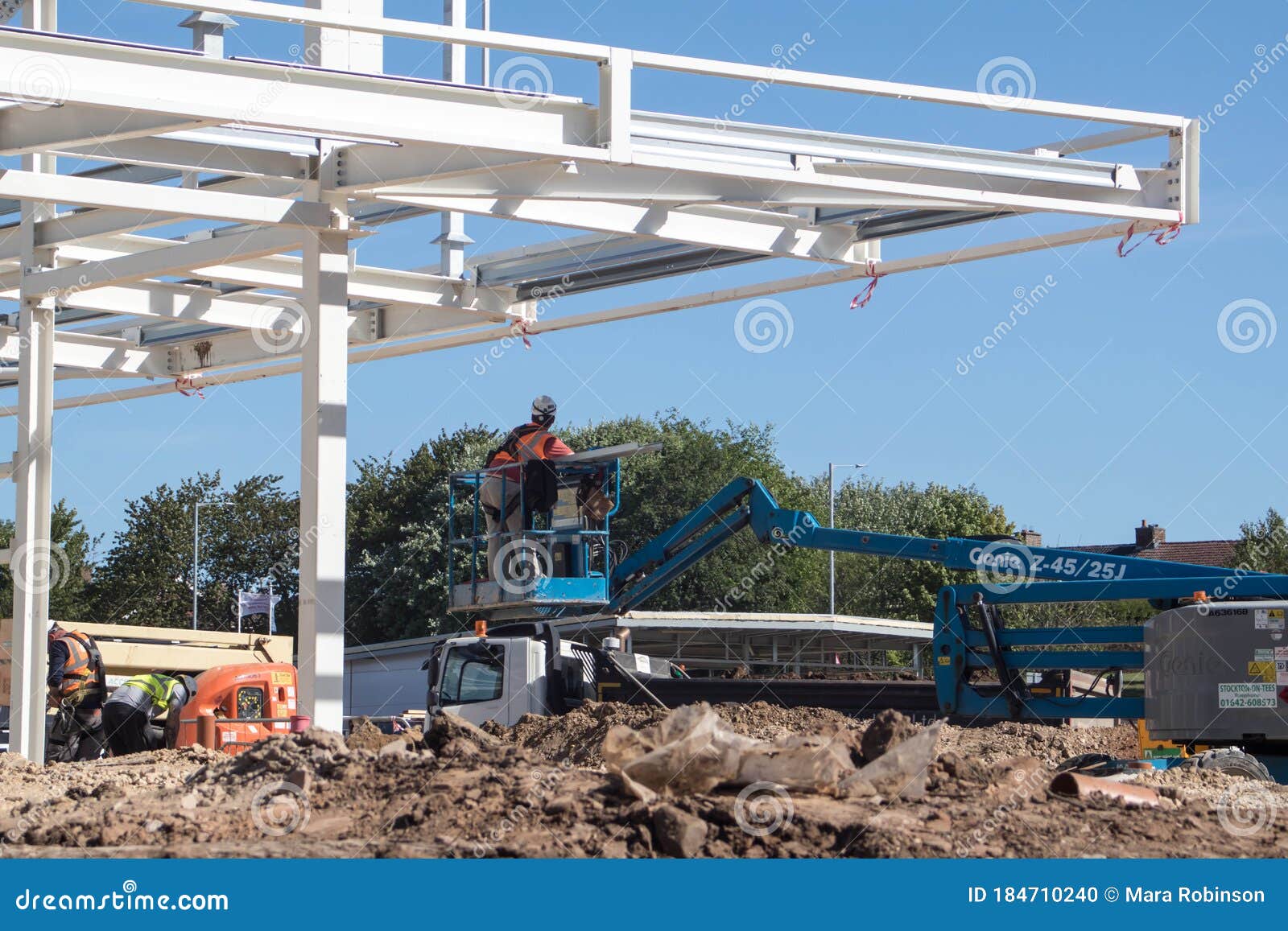 Construction Worker in a Cherry Picker Crane beside the Frame of a New ...
