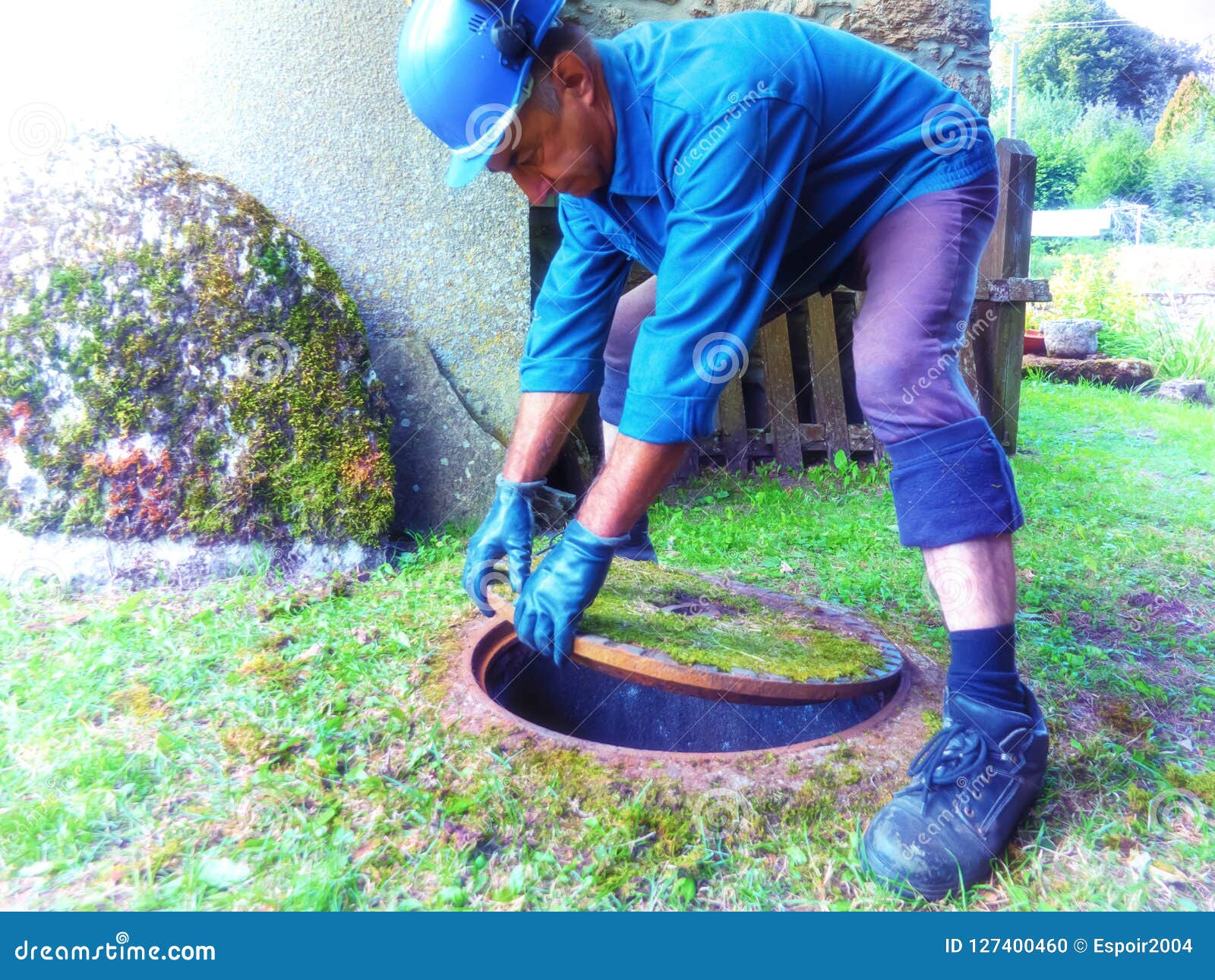 A Worker in a Special Garment for Construction Works Opens a Manhole in ...