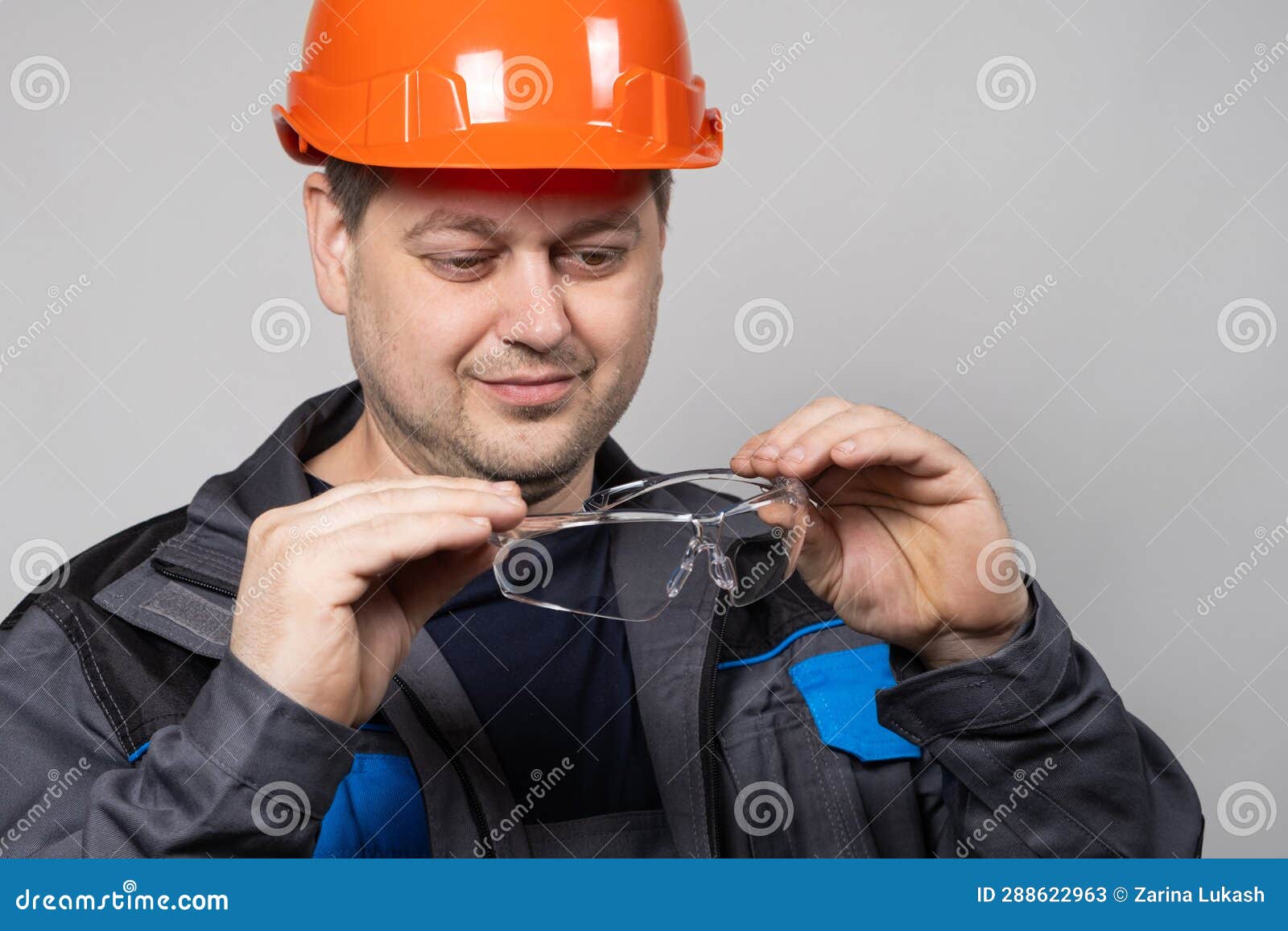 A Construction Worker in a Helmet and Overalls Put on Goggles ...