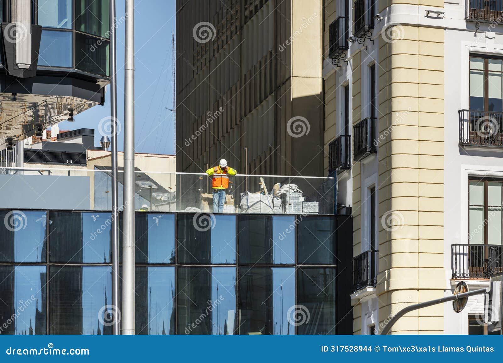A Construction Worker Leaning on a Railing of a Building Under ...