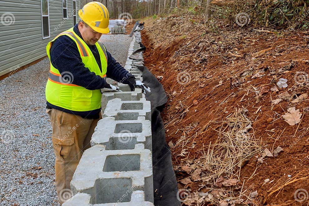 Construction Worker is Mounting a Retaining Wall Using Concrete Blocks ...