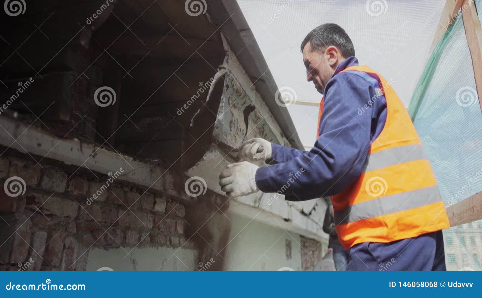 Construction Worker in Orange Uniform Vest Breaks Dirty Old Wooden Wall ... Construction Worker in Orange Uniform Vest Breaks Dirty Old Wooden Wall ...