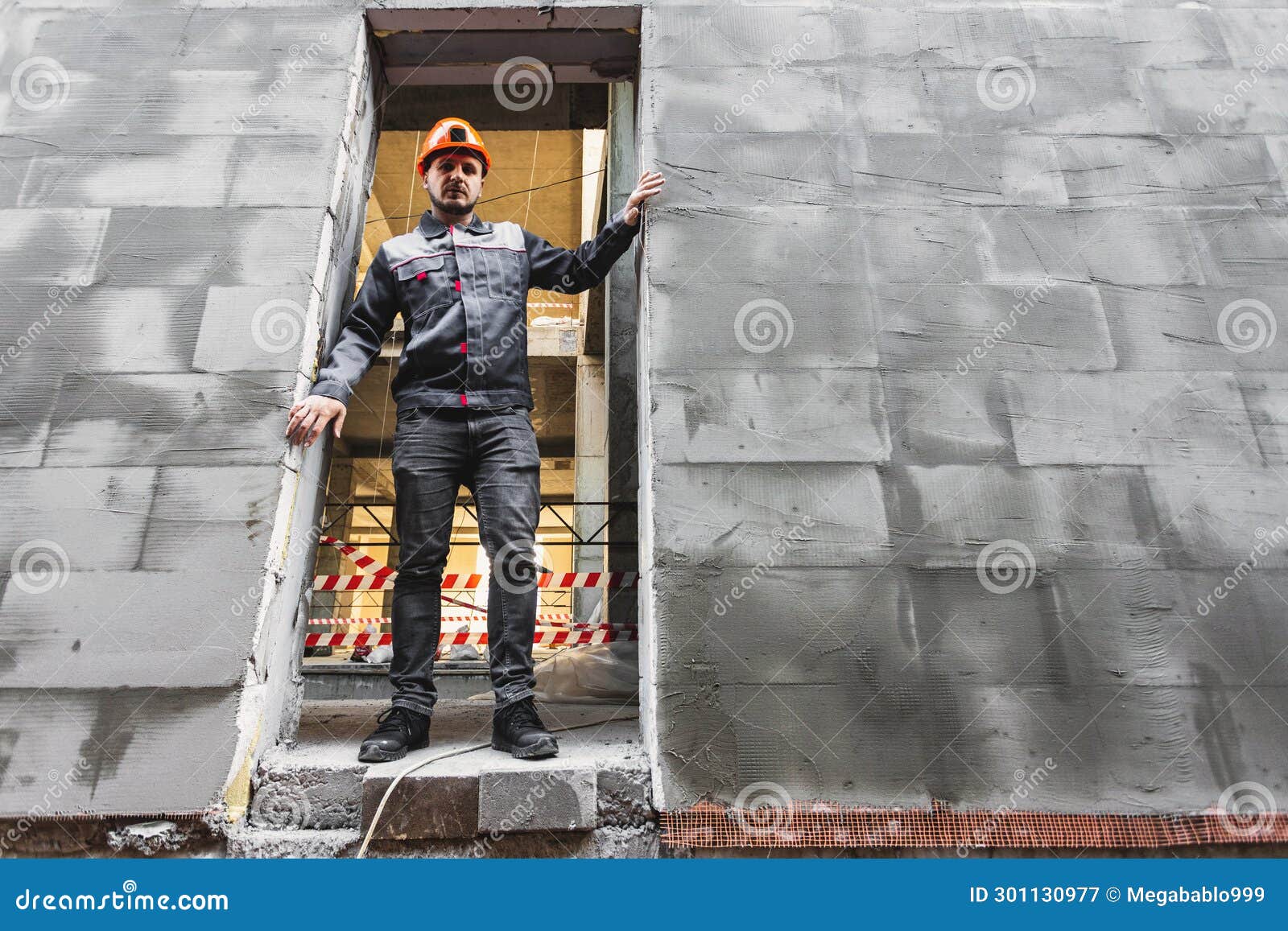 A Construction Worker in Overalls Stands in the Opening of a Building ...
