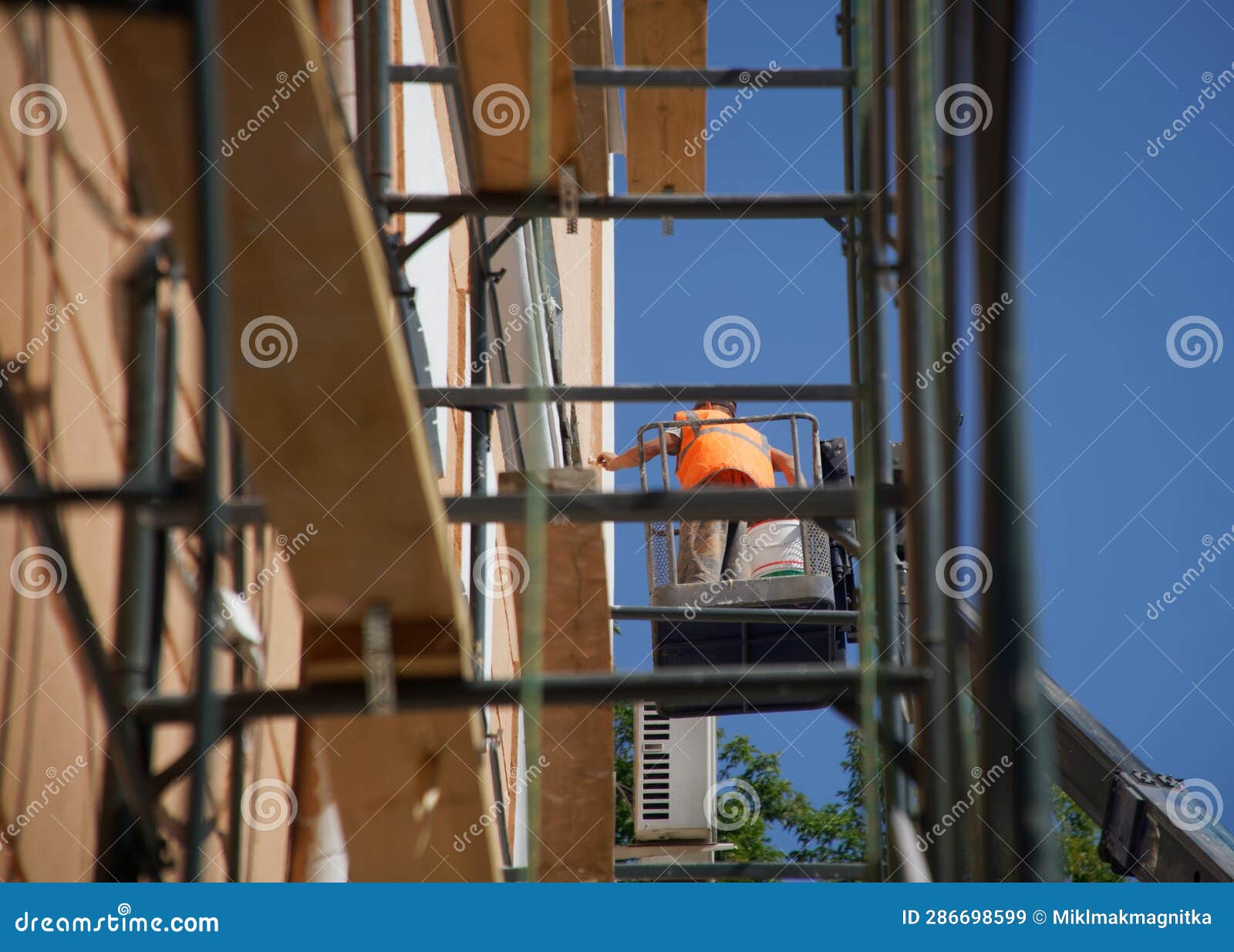 Construction Worker-plasterer in a Cradle Lift and Scaffolding Next To ...