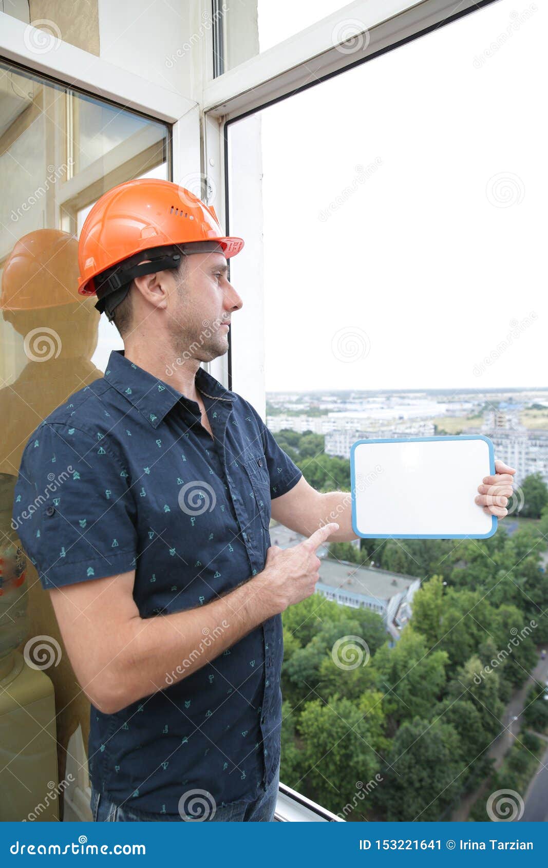Construction Worker in a Protective Helmet with a Tablet for Writing in ...