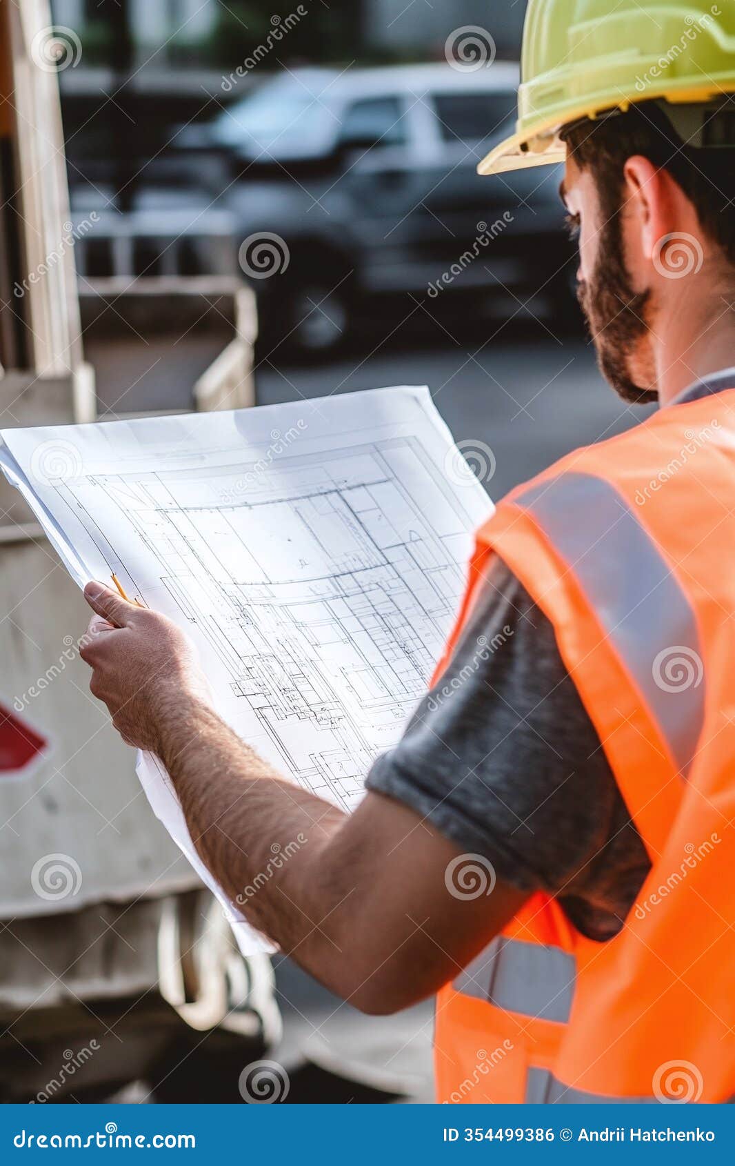 Construction Worker Reviewing Blueprints while Adhering To Safety ...