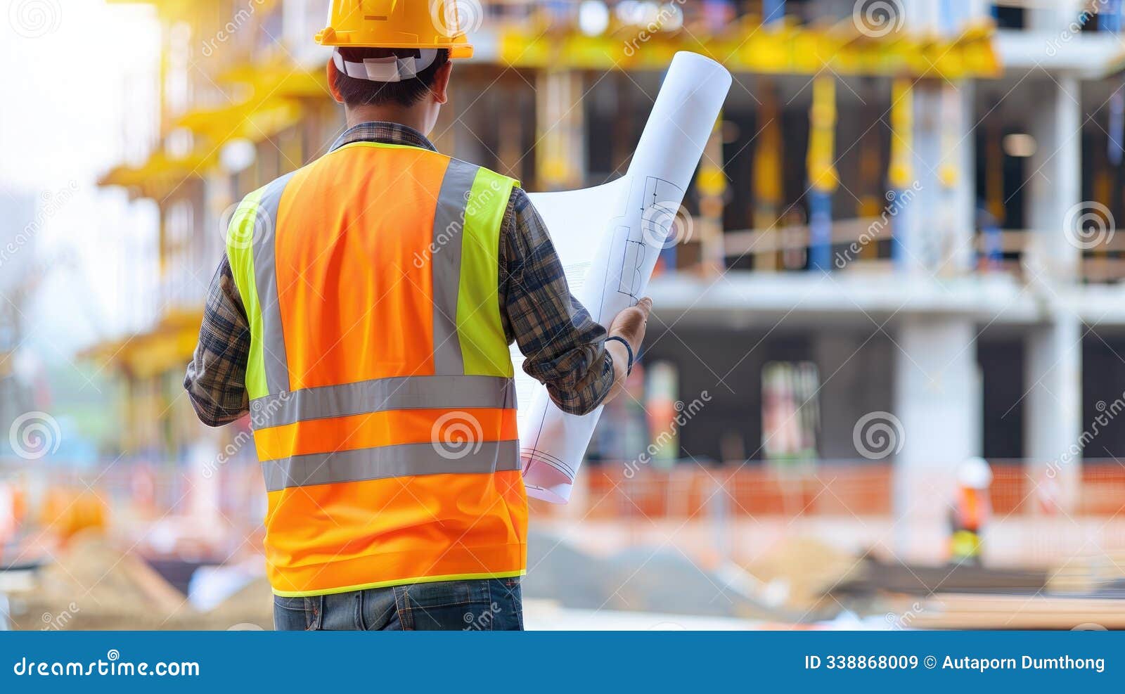 Construction Worker in Safety Gear Holds Blueprints, Overseeing a ...