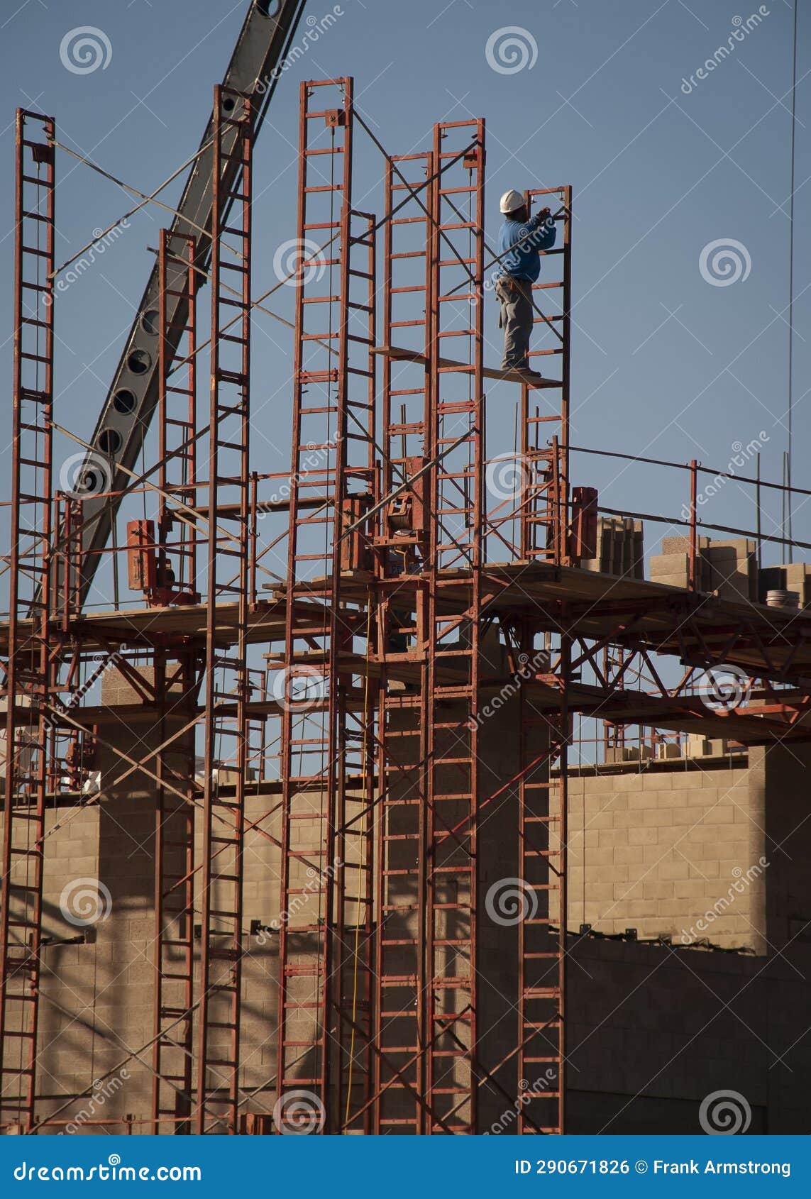 A Construction Worker Standing on Metal Scaffolding Against a Blue Sky ...