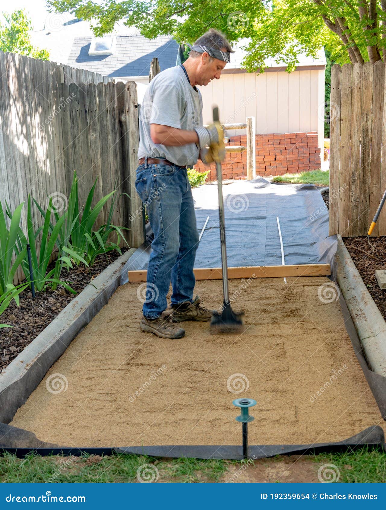 Construction Worker Tamps Sand Flat in Preparation of a Walking Path ...