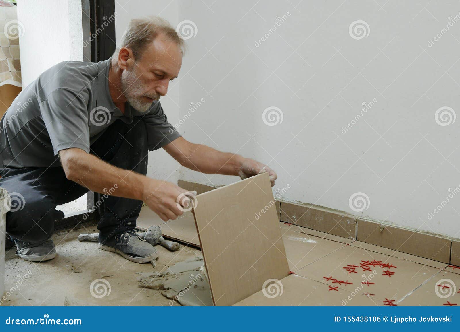 Construction Worker is Tiling Floor at Home. Laying Tiles on the Floor ...