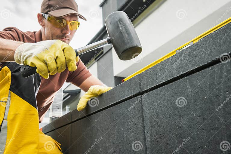 Construction Worker Using a Hammer To Align Blocks while Building a ...