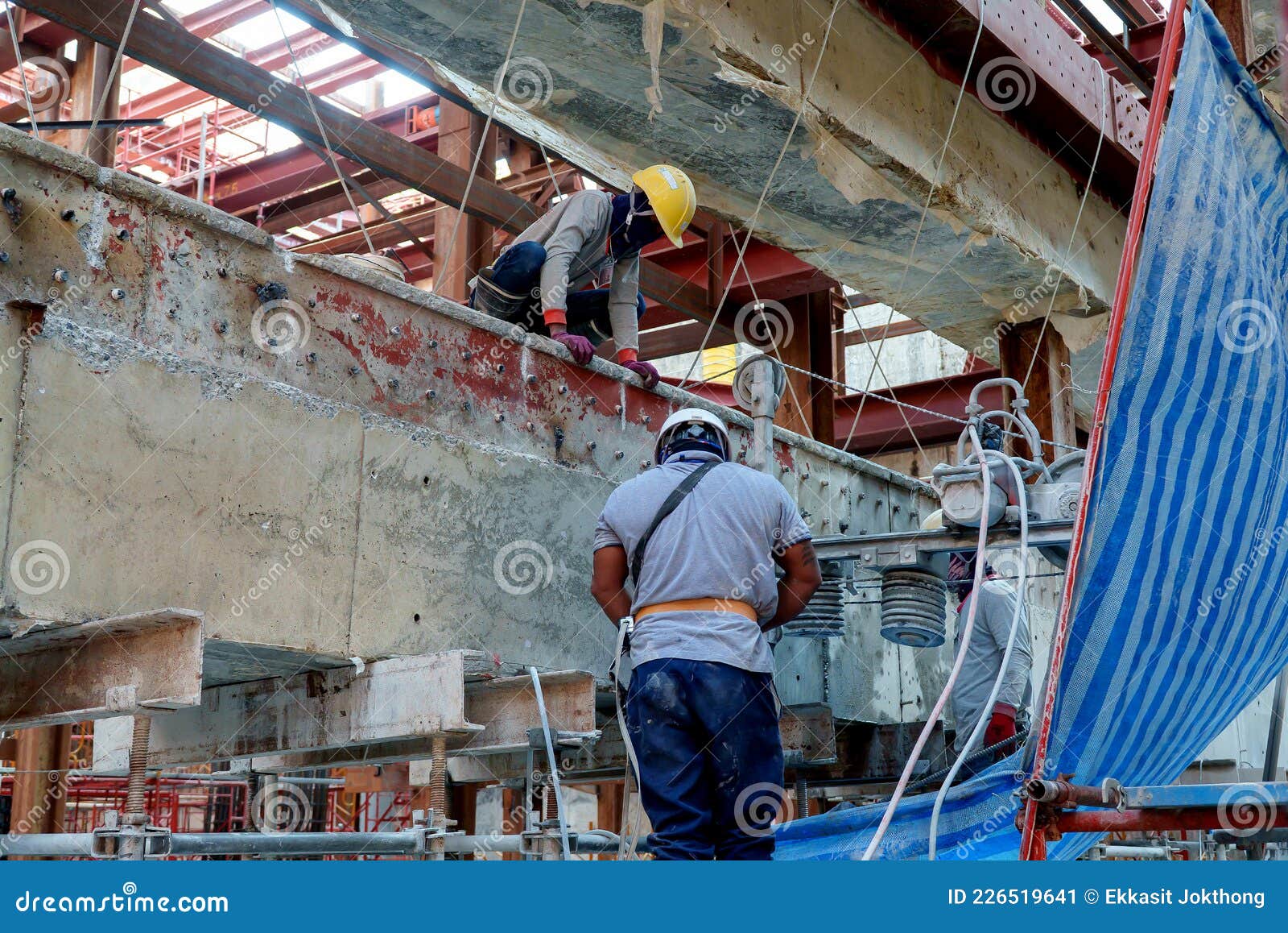 A Construction Worker is Using a Machine To Cut Cement Beams in a ...