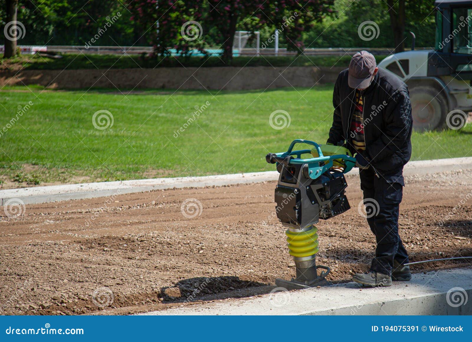 A Construction Worker Work-hardens a Sandy Ground with a Vibrat ...