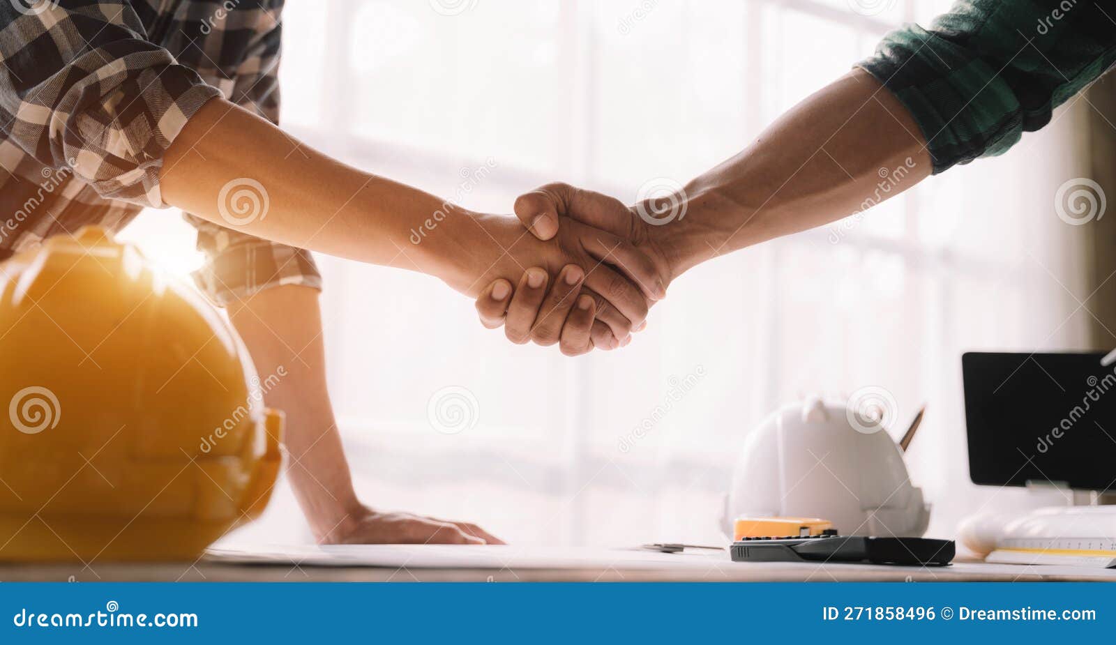 Two Engineers Shake Hands While Looking At A Floor Plan During ...