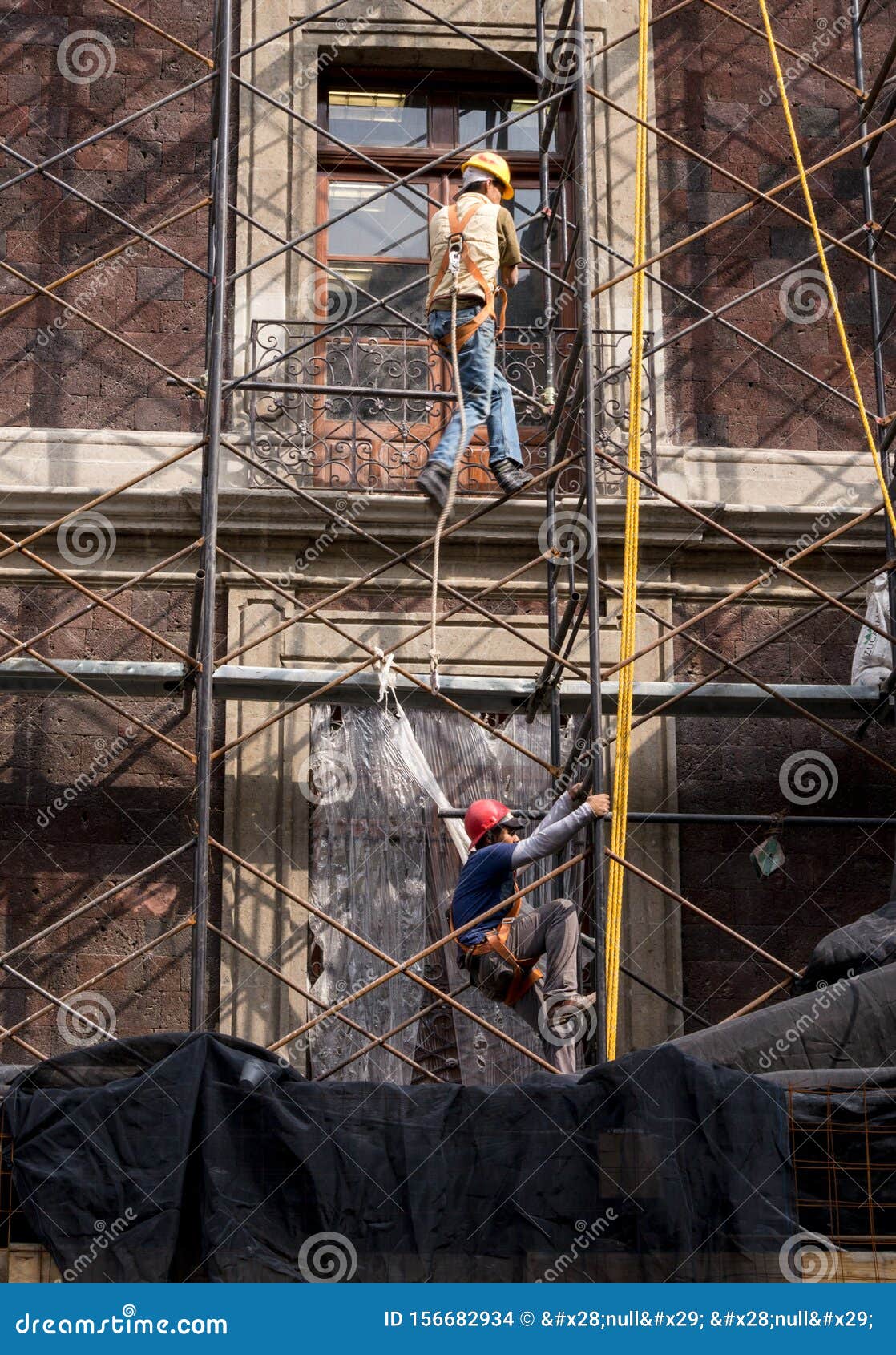 Workers Wearing Helmets Are Pulling A Heavy Rope At Night, Showing ...