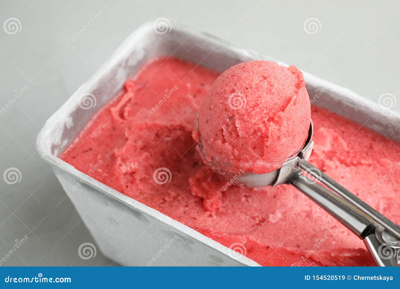 Container with Delicious Pink Ice Cream and Scoop on Grey Table Stock ...