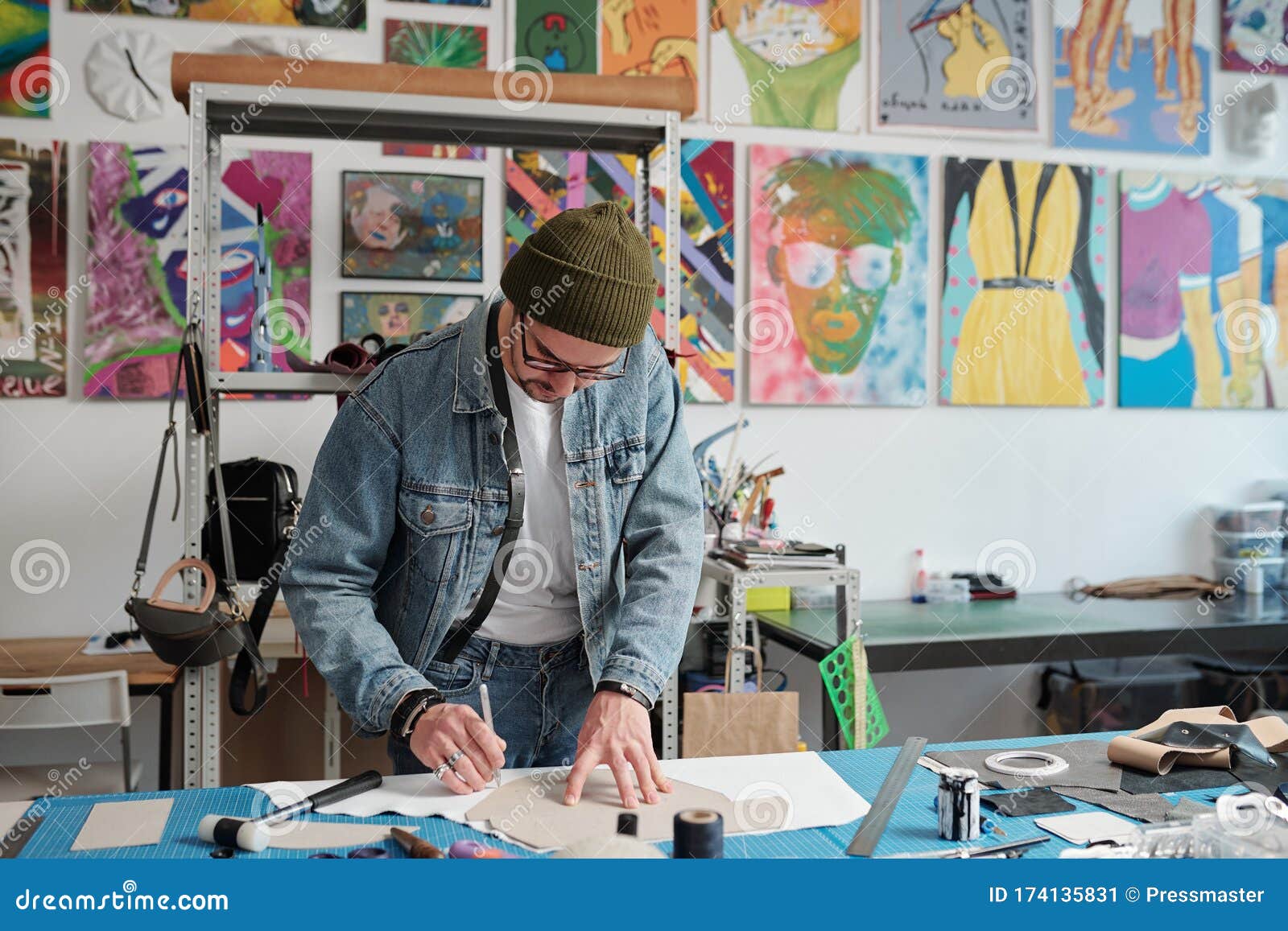 Contemporary Leatherworker Bending Over Table while Outlining Paper ...