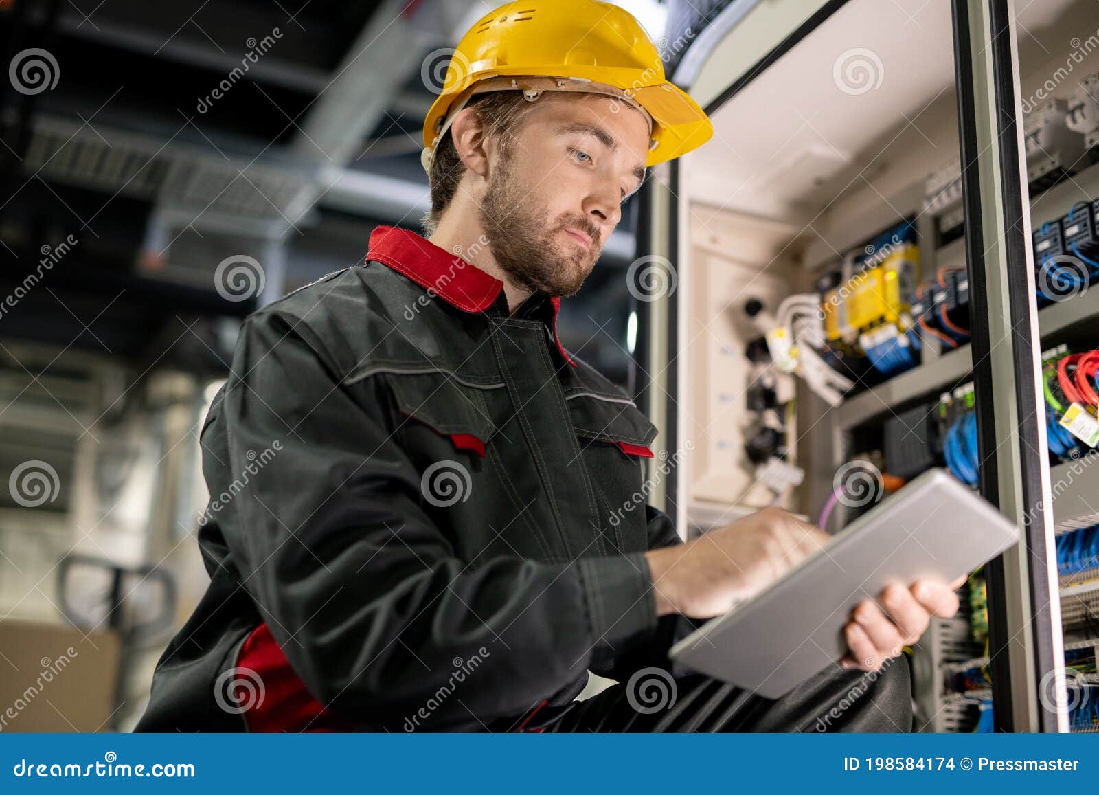Young Serious Engineer in Workwear and Hardhat Scrolling through ...
