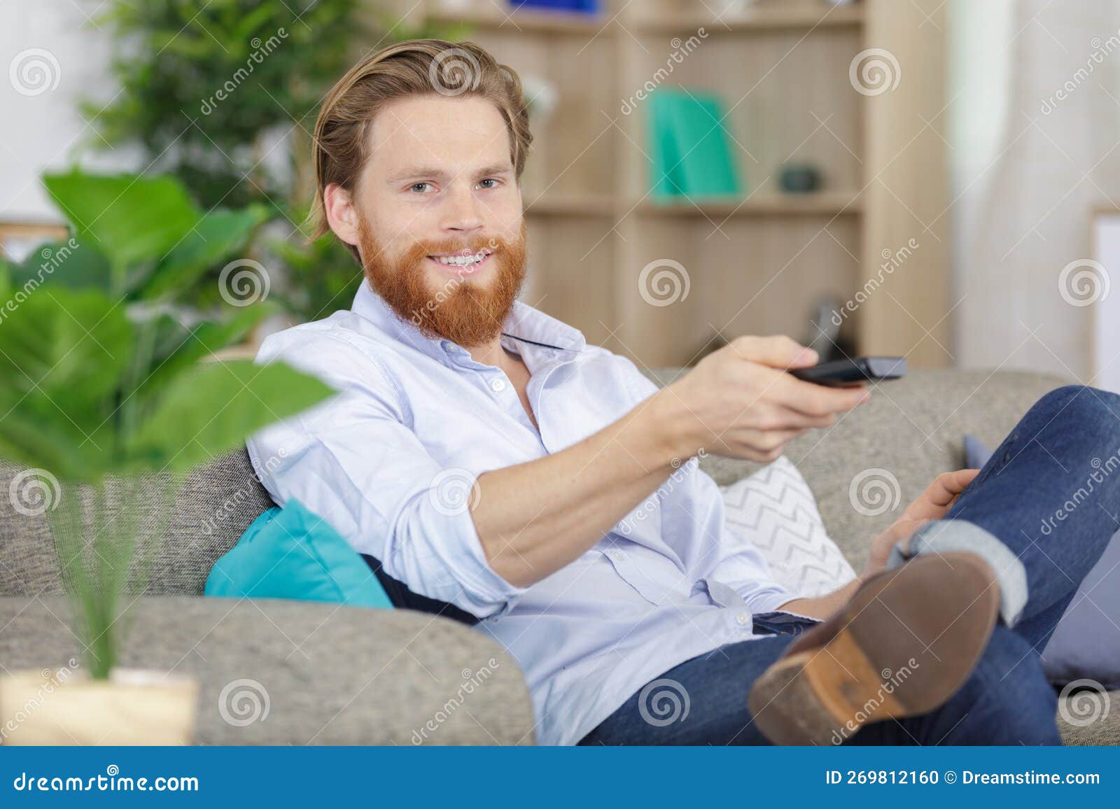 Contented Man on Sofa Using Tv Remote Control Stock Photo - Image of ...