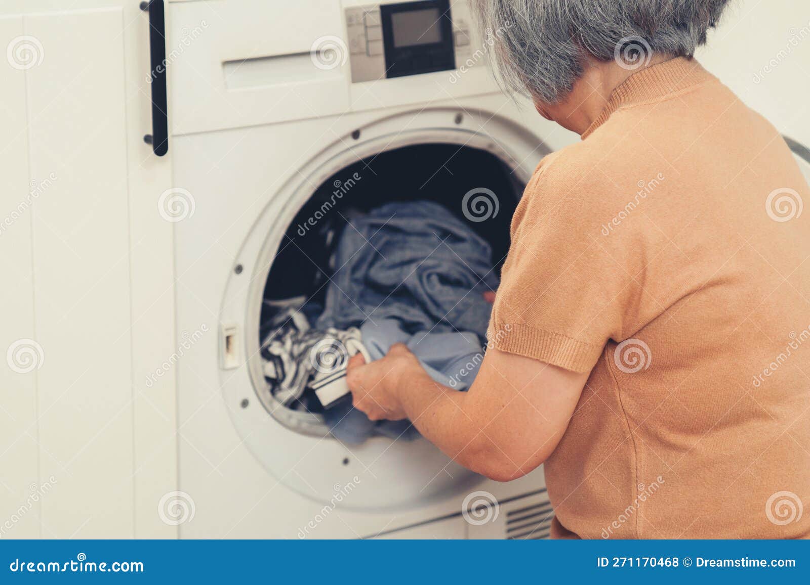 Contented Senior Housewife Doing Laundry In The Laundry Room Stock