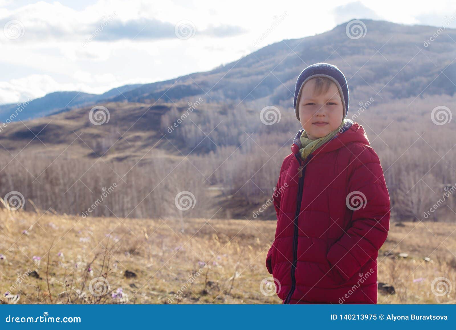 A Contented Six-year-old Boy in a Warm Red Jacket Keeps His Hands in ...