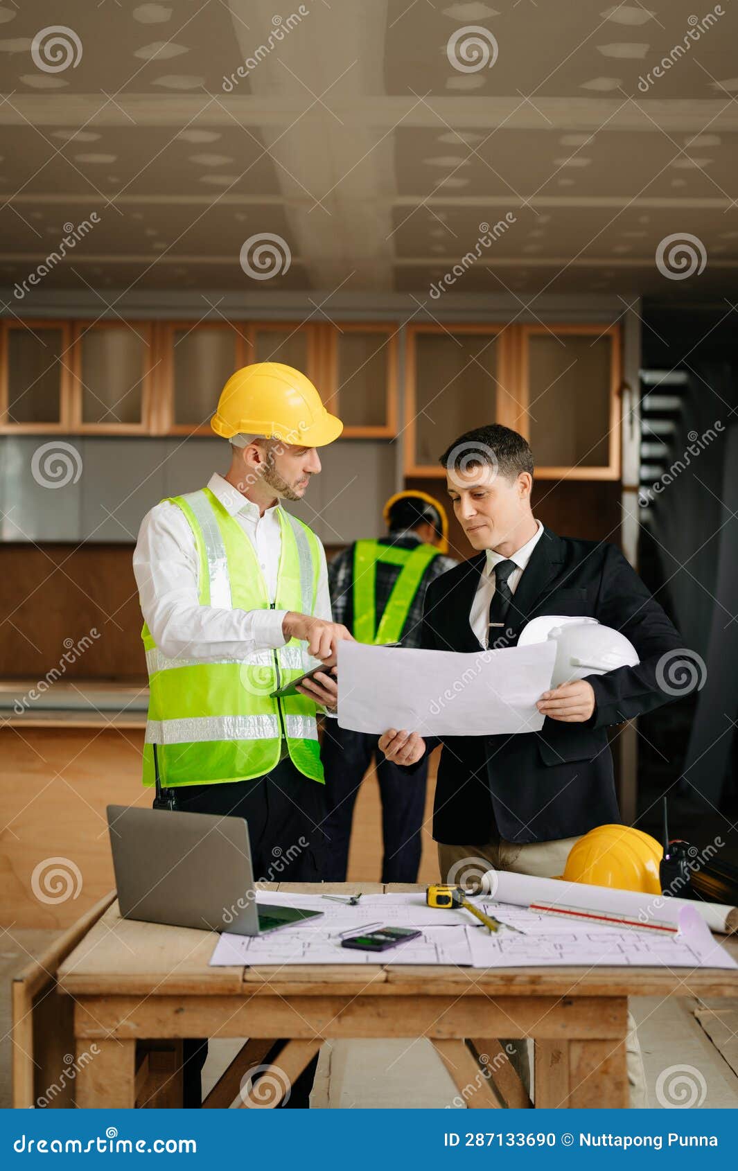 Contractor and Architect Looking at Plan, Tablet, Laptop and Talking ...