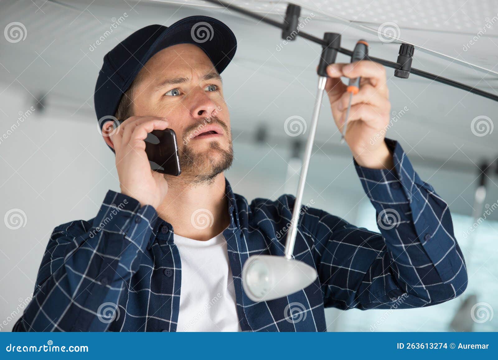 Contractor Fixing Spotlamp To Ceiling and Talking on Smartphone Stock ...