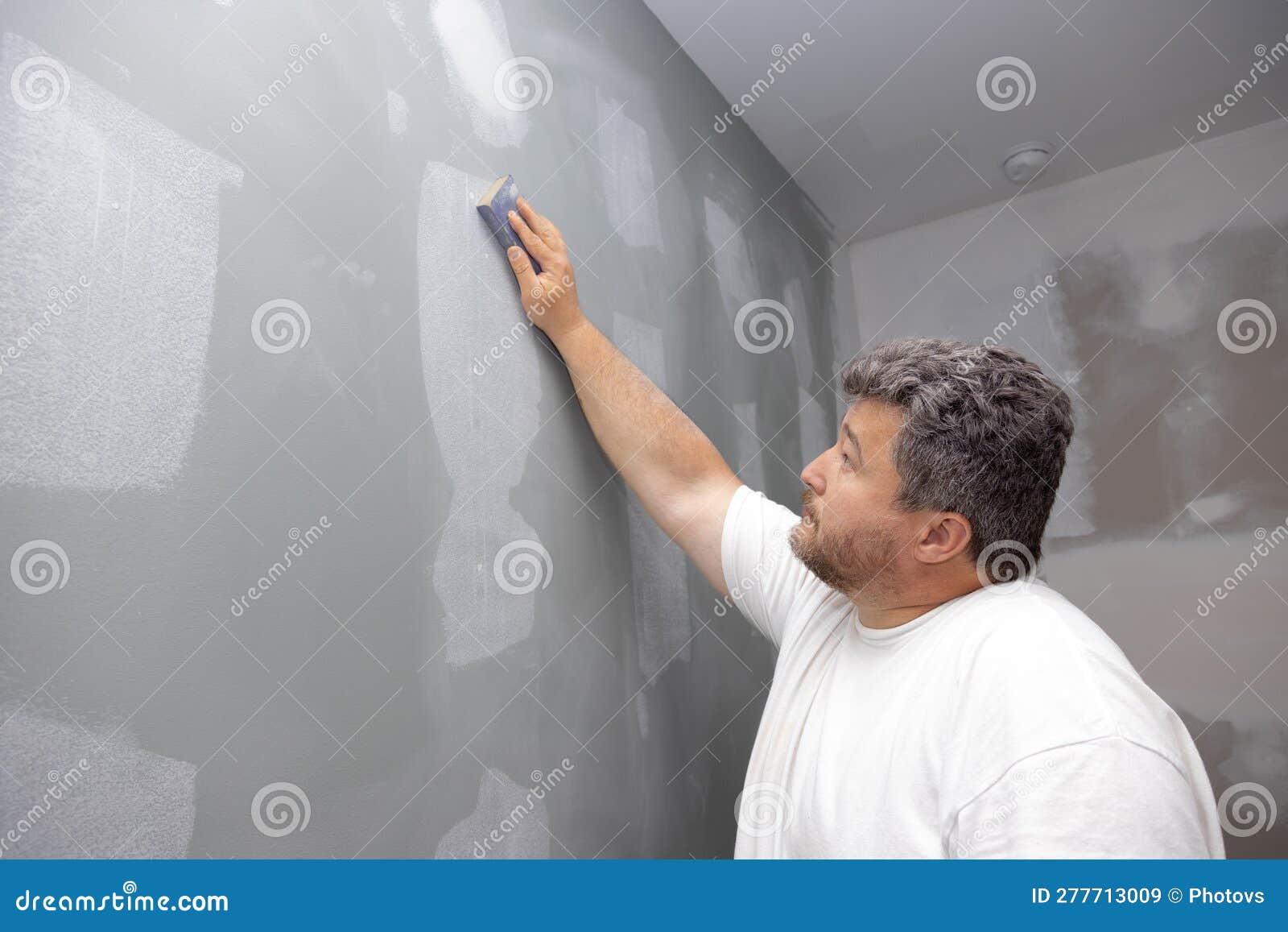 A Contractor is Sanding the Wall after Putting Up Putty As Part of a ...