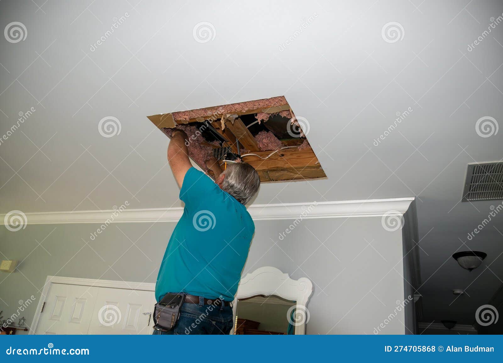 A Contractor is Seen Working through a Hole in the Ceiling of a House ...