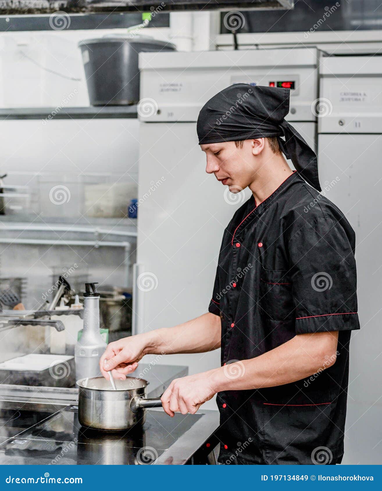 A Cook in Black Uniform Working at the Kitchen of the Restaurant Stock ...