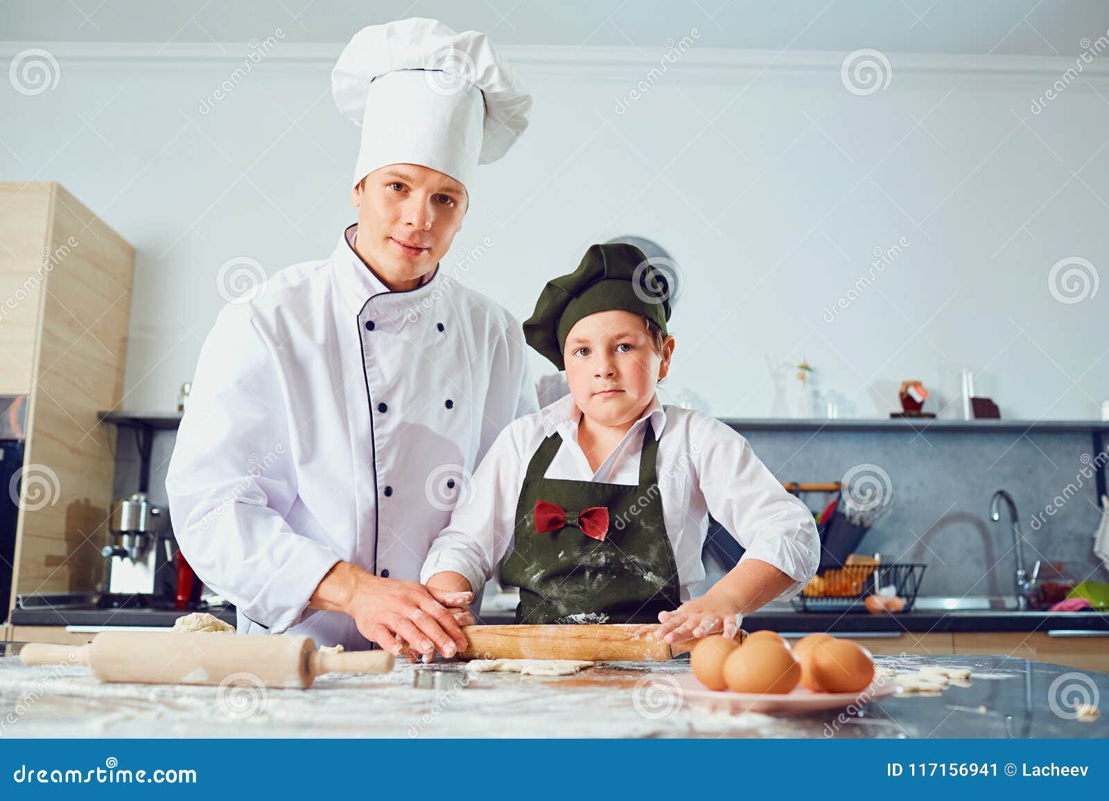 Cook with the Boy in the Uniform of the Cook in the Kitchen. Stock ...