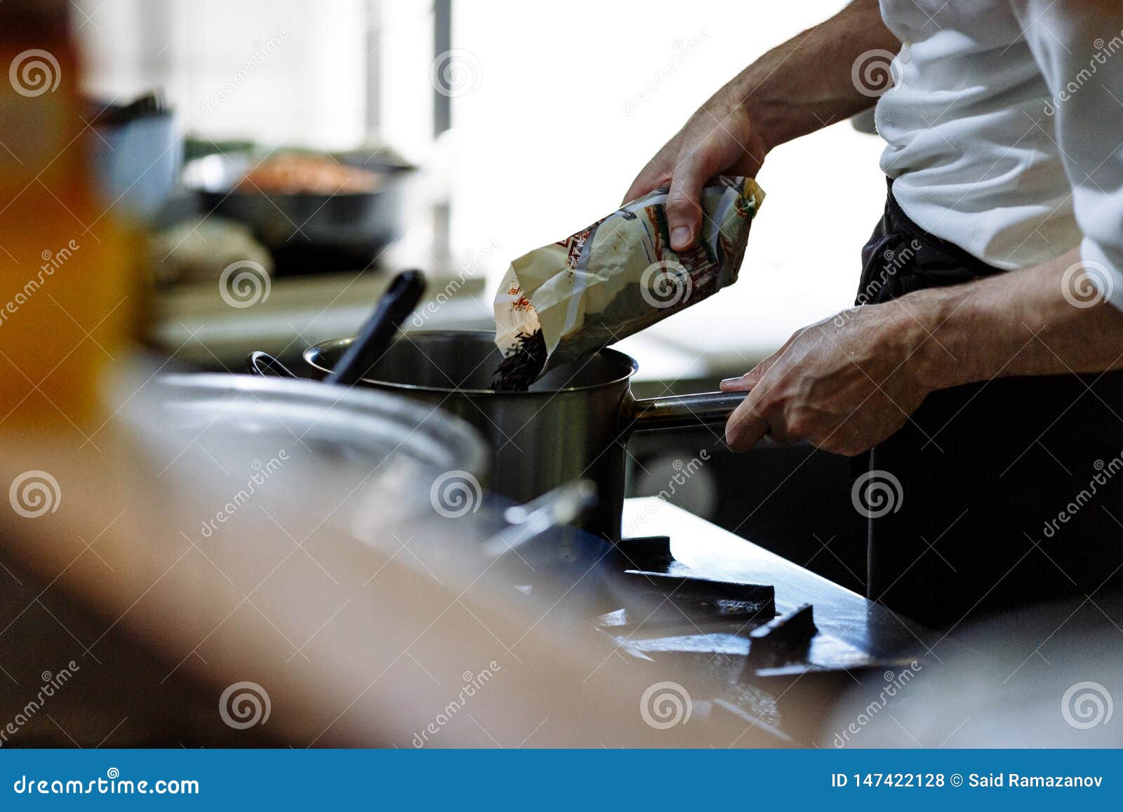 Cook Cooks in a Restaurant Kitchen, Sprinkles Spices into the Pan Stock ...