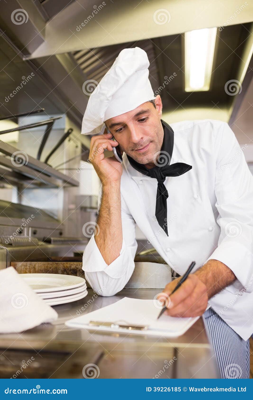 Cook Writing on Clipboard while Using Cellphone in Kitchen Stock Image ...