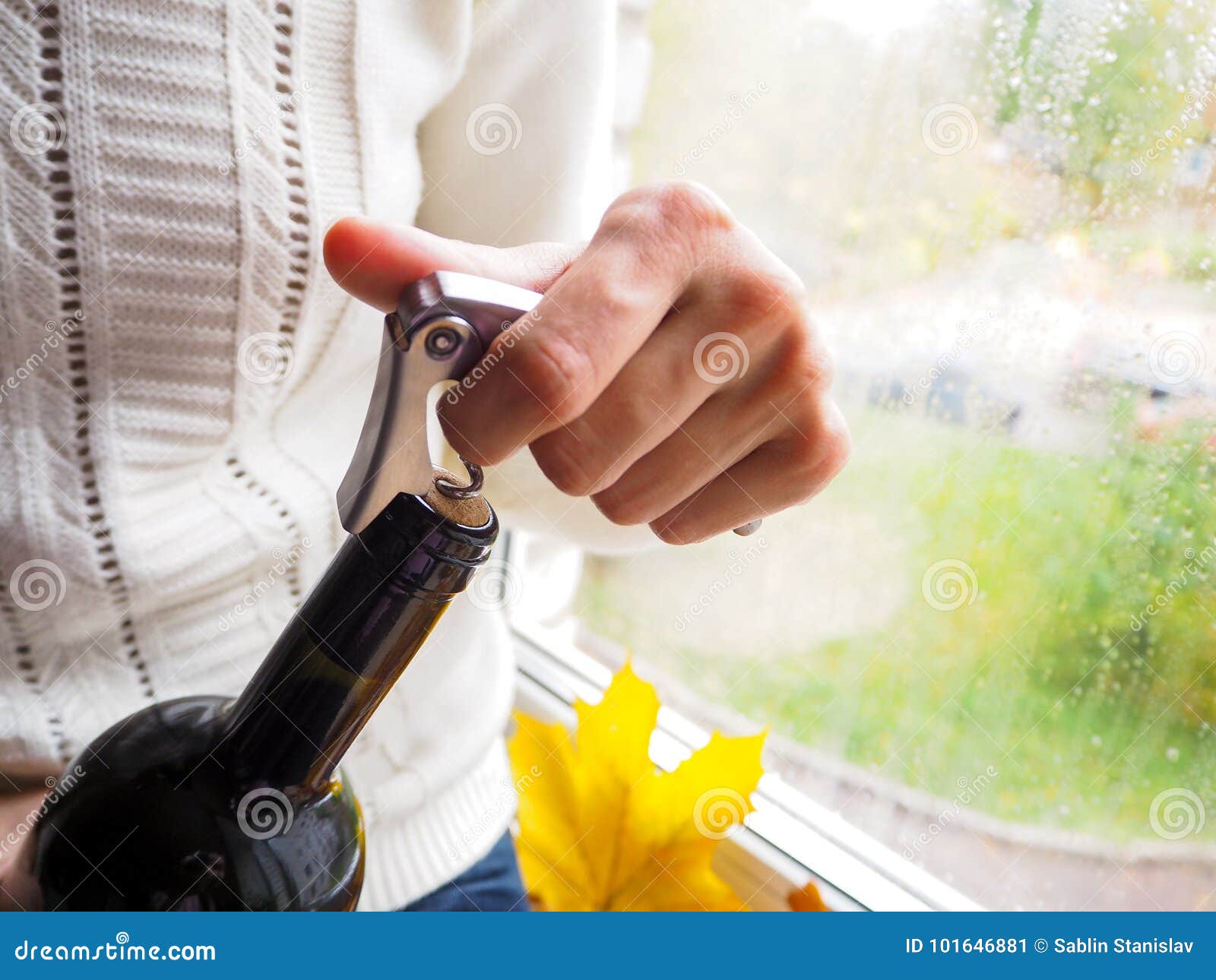 Lady Sitting on the Windowsill Opens a Bottle of Wine with a Corkscrew ...
