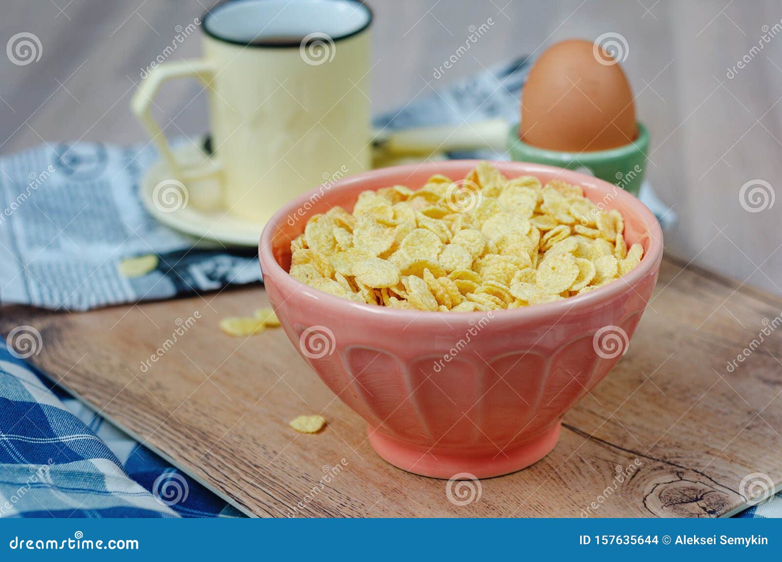 Corn Flakes in a Pink Bowl, a Mug with Tea and Boiled Egg, on a Wooden ...