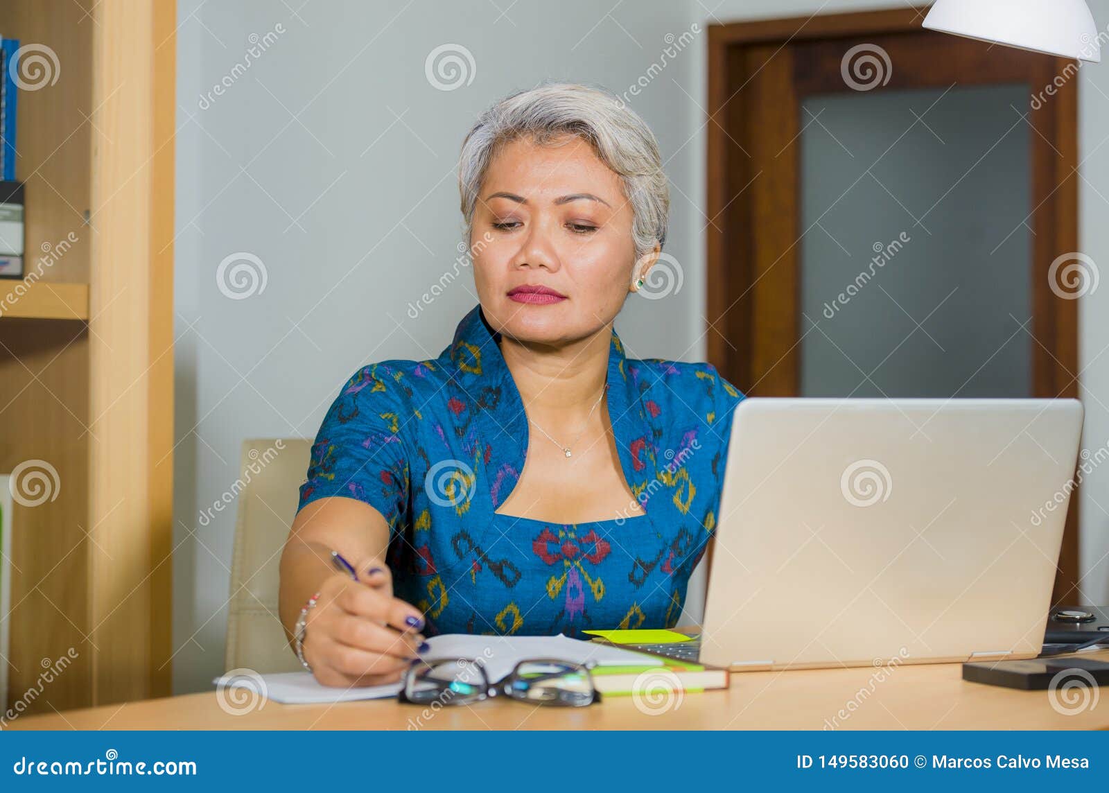 Busy And Concentrated Attractive Middle Aged Asian Woman Working At
