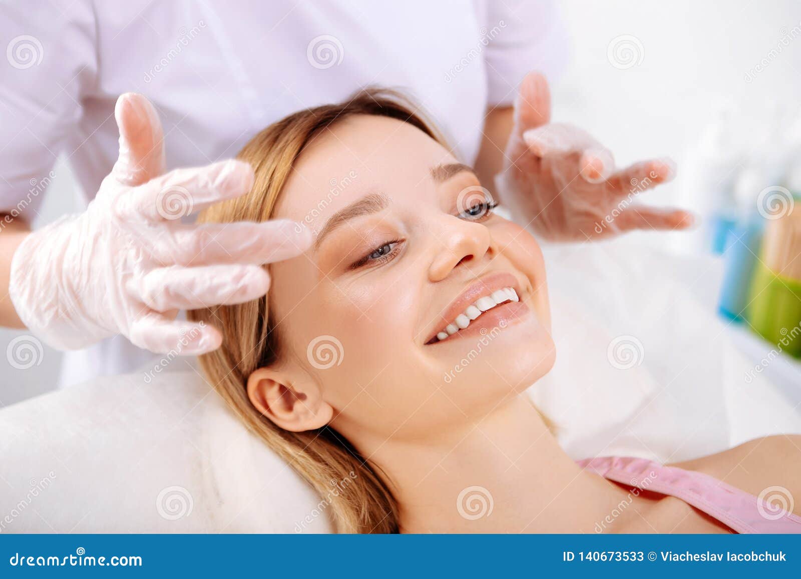 Cosmetologist Making Face Massage Of Beautiful Smiling Client Stock
