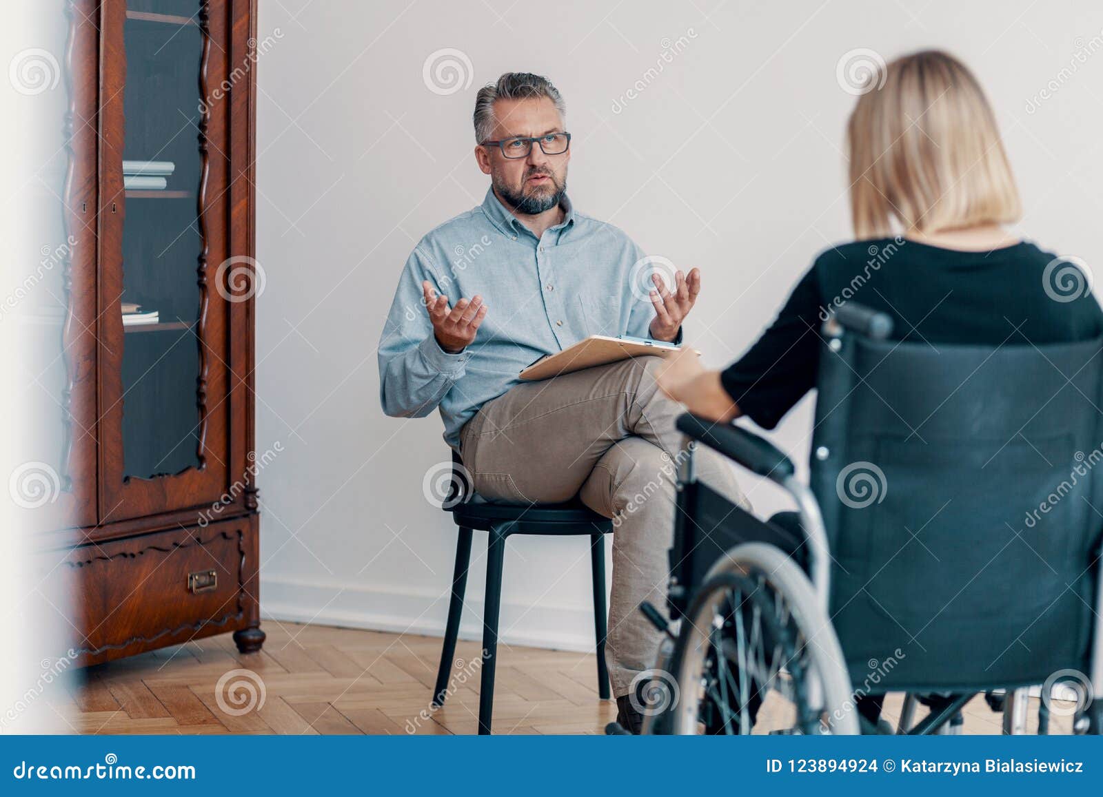 Counselor Talking To A Disabled Woman In A Wheelchair In His Off Stock