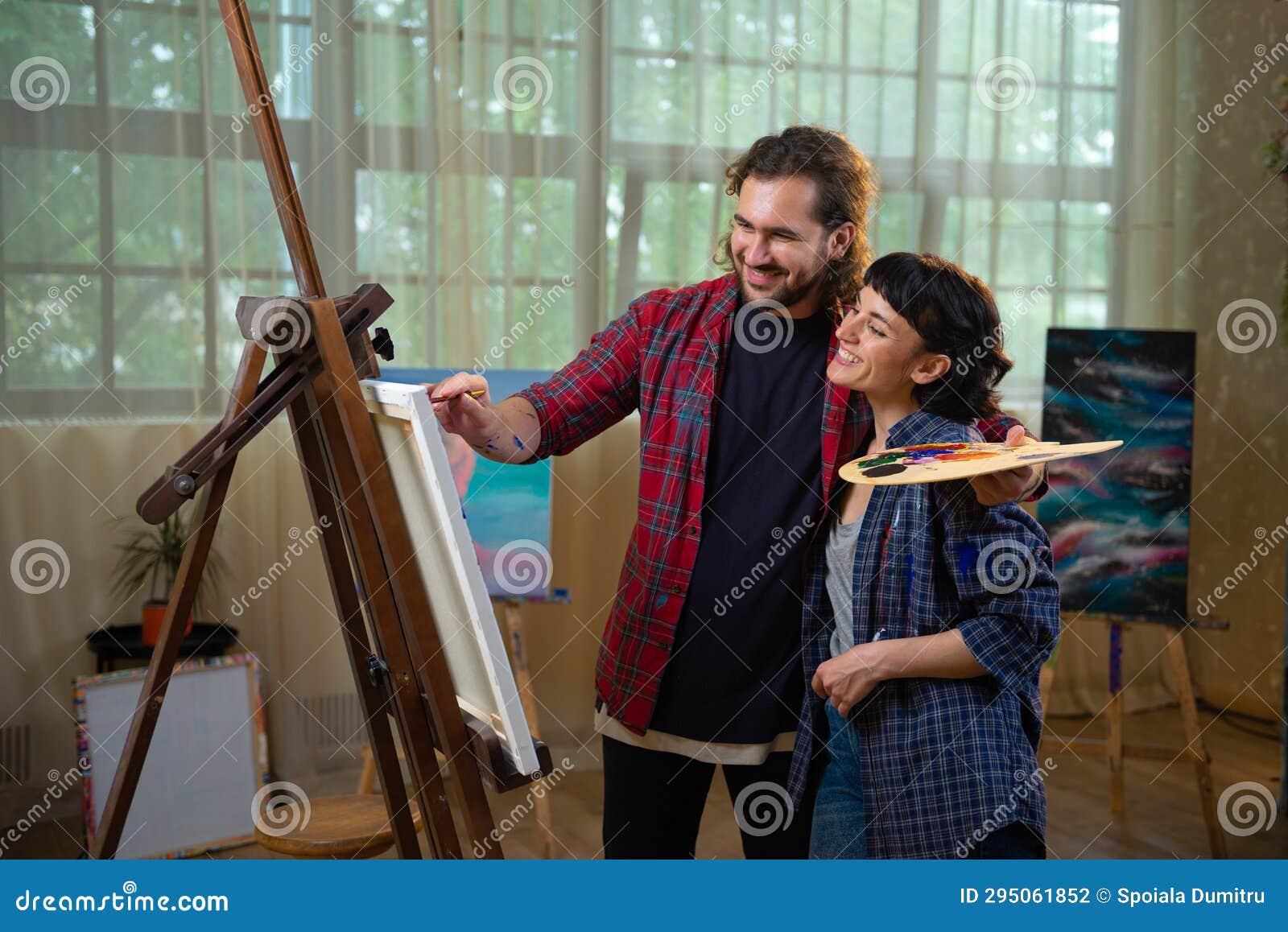 Couple of Artists Sitting in Their Studio Use Laptop Computer, Working ...