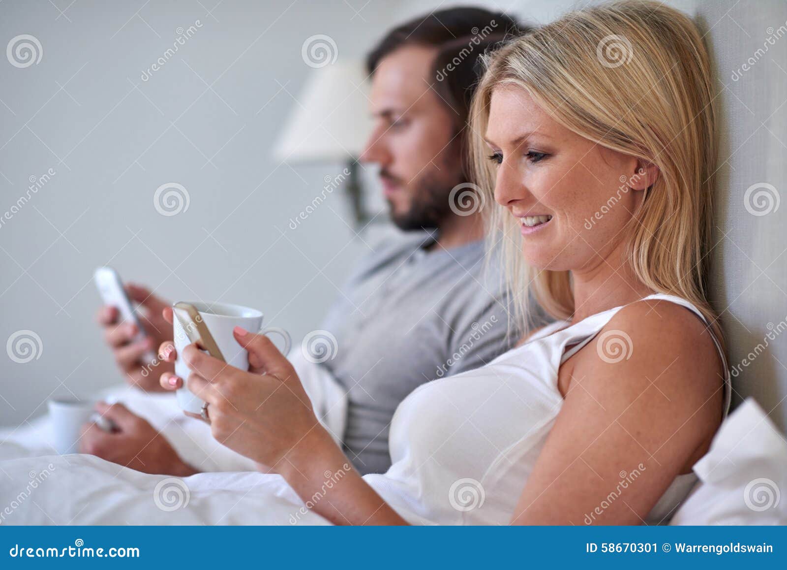 Couple cellphone bed stock image. Image of concentrating - 58670301