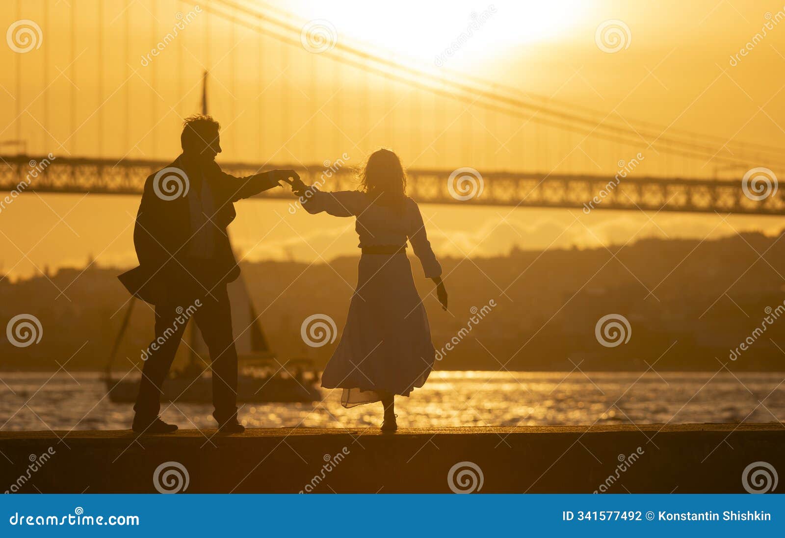 Couple Dancing by River at Sunset with Bridge in Background Stock Photo ...