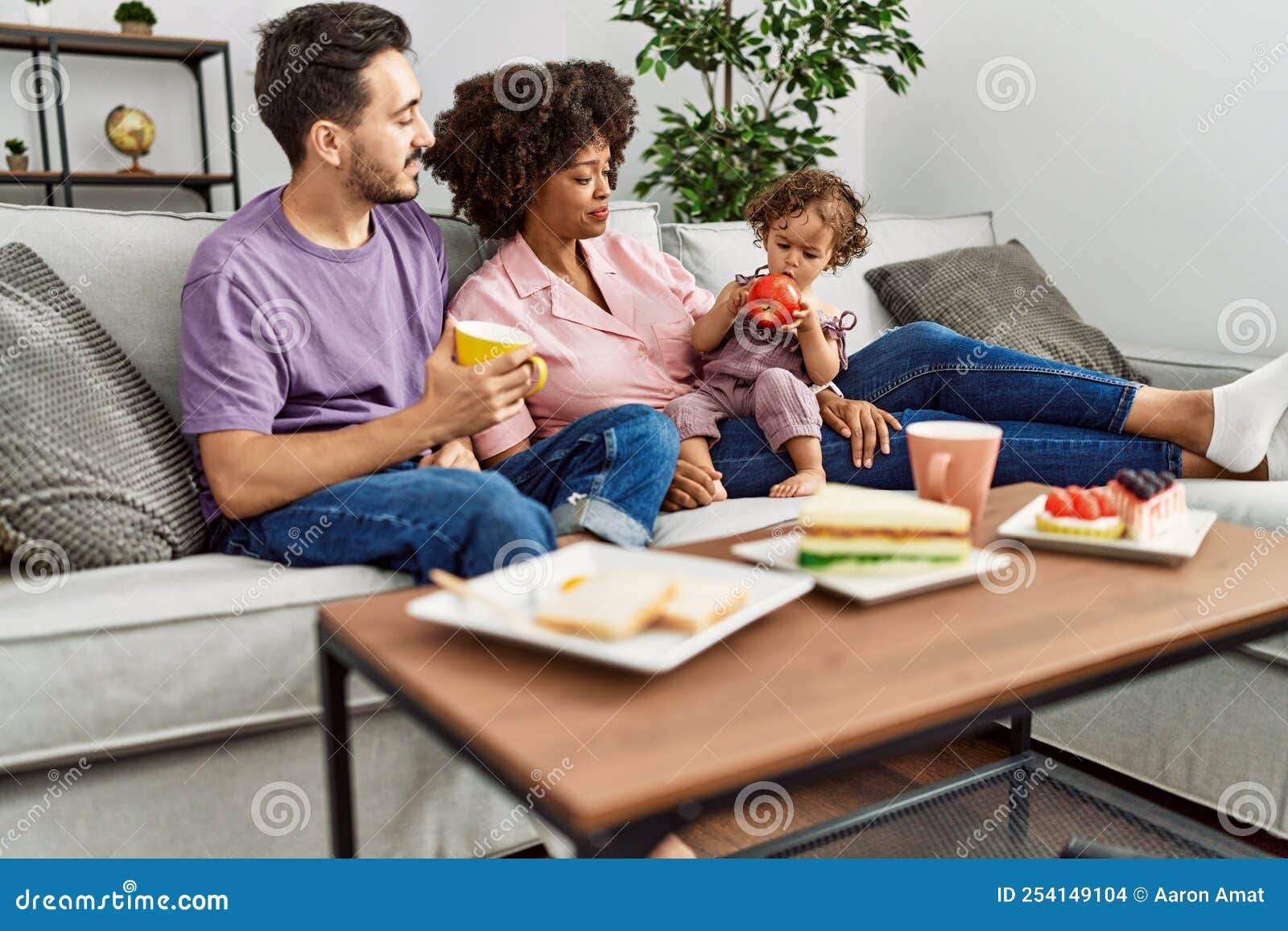 Couple and Daughter Having Breakfast Sitting on Sofa at Home Stock ...
