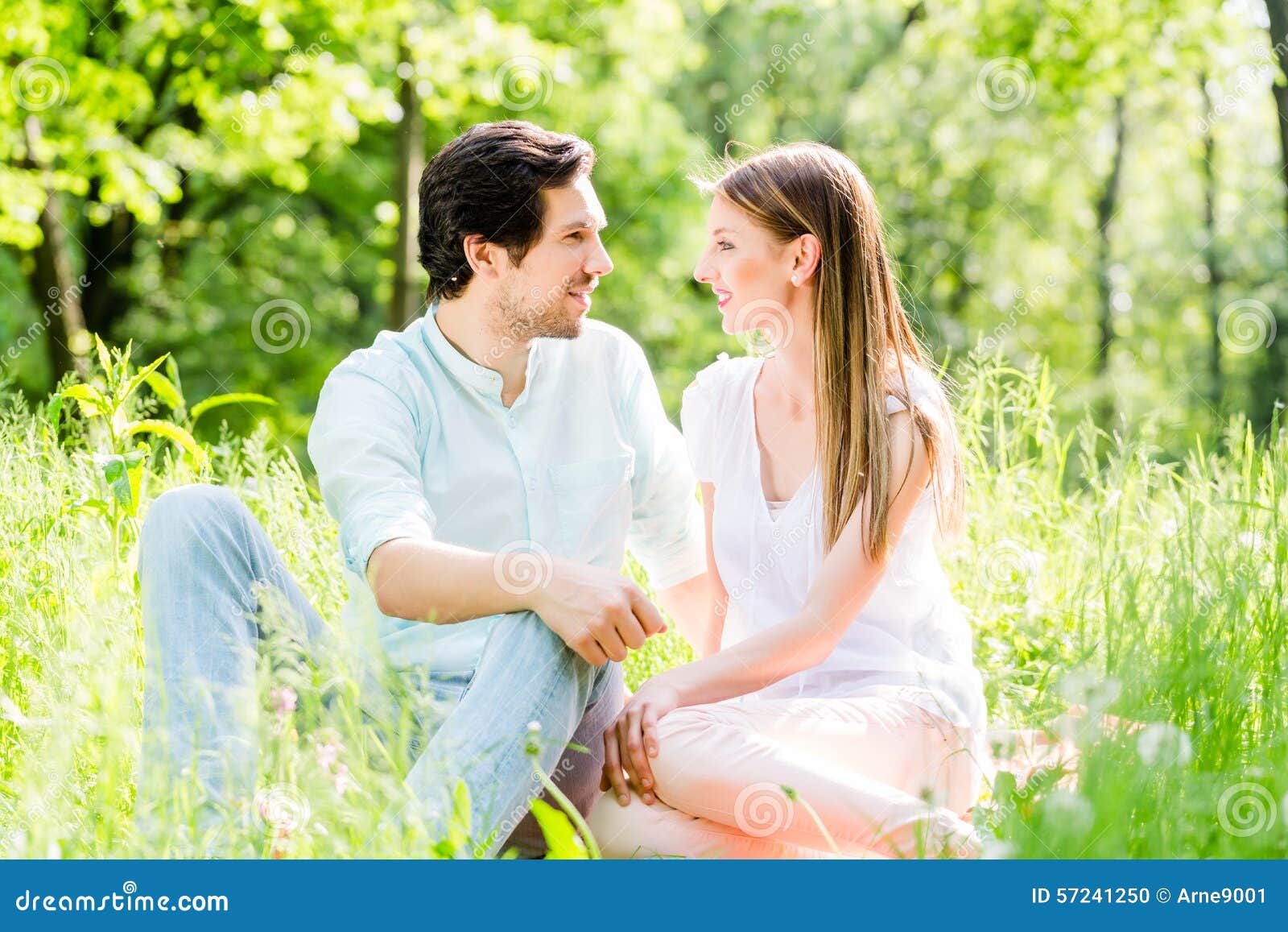 Couple in Grass on Meadow Looking at Each Other Stock Photo - Image of ...