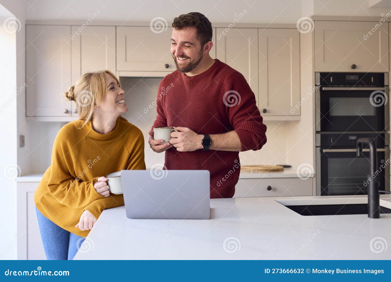 Couple at Home Looking at Laptop on Counter in Kitchen Together Stock ...