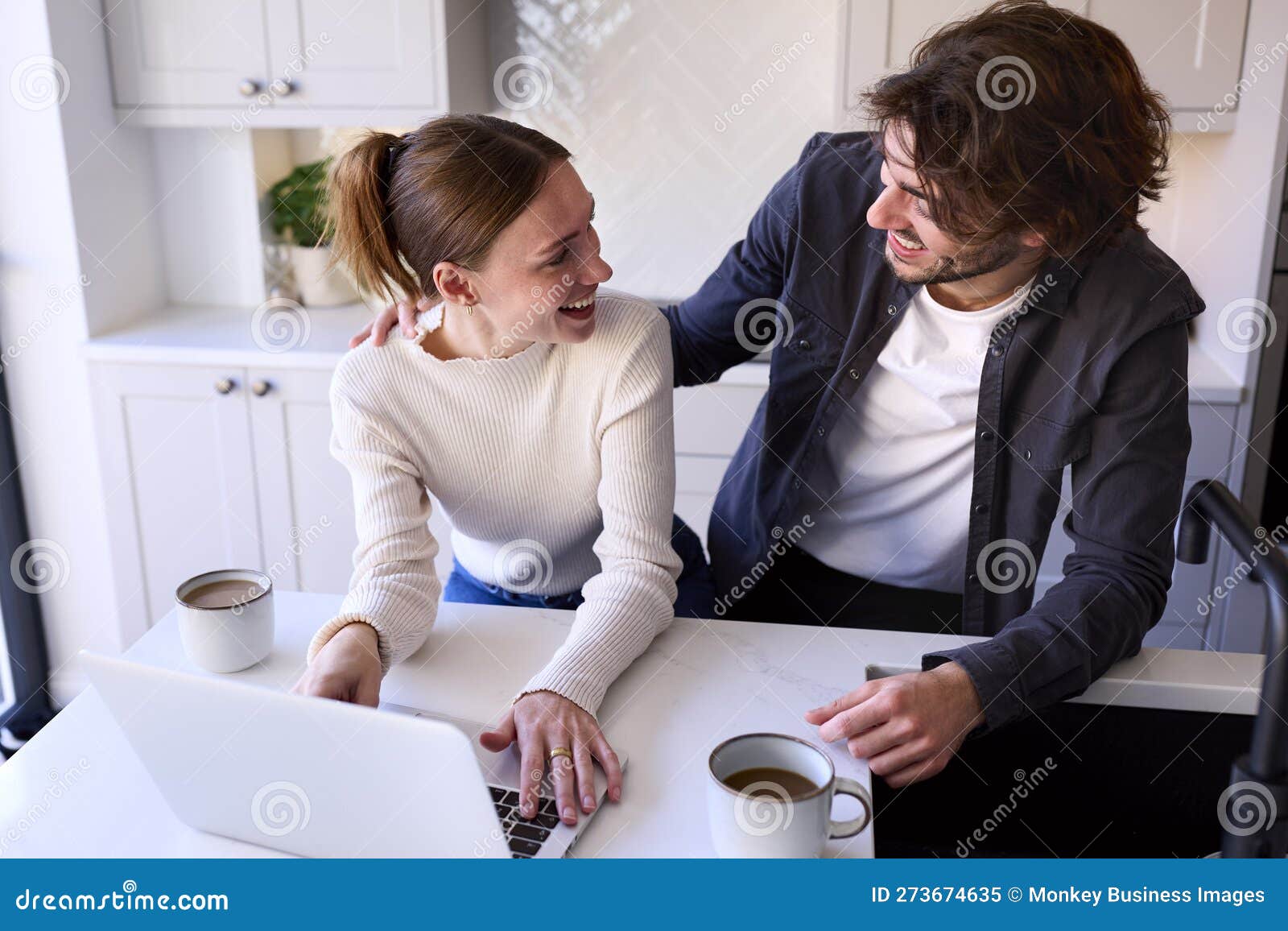 Couple at Home Looking at Laptop on Counter in Kitchen Together Stock ...