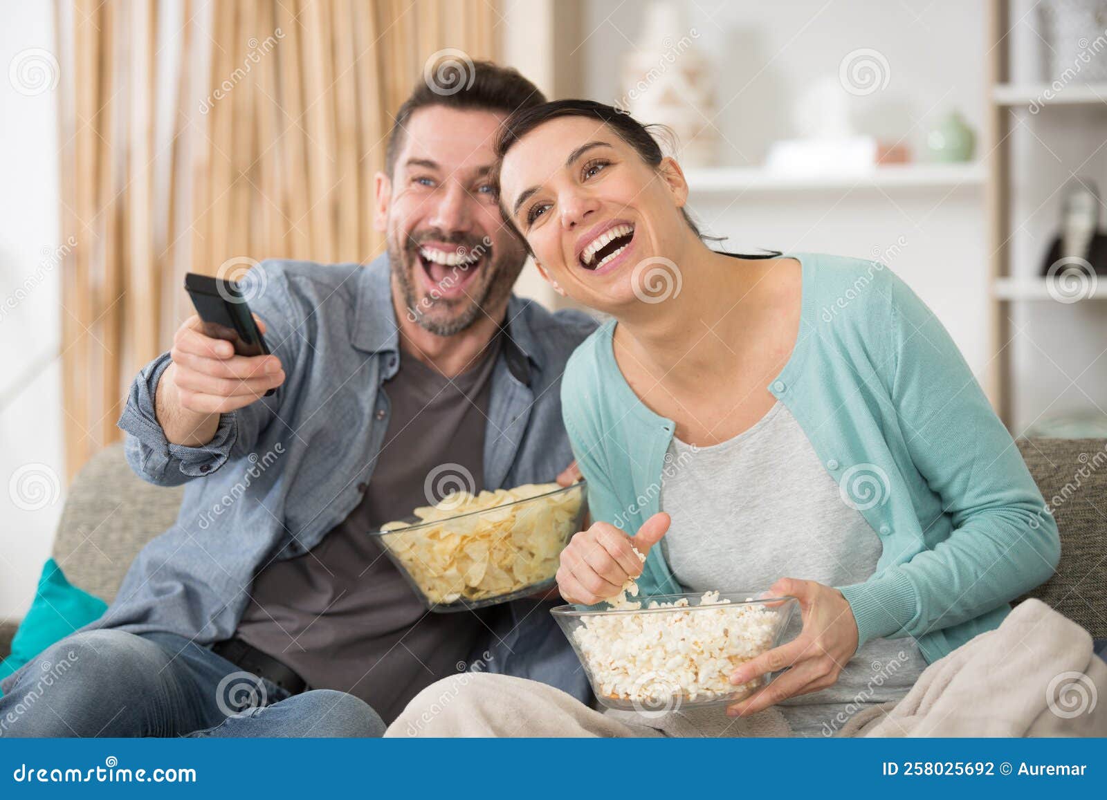 Couple Laughing and Eating Snacks while Watching Tv Stock Photo - Image ...