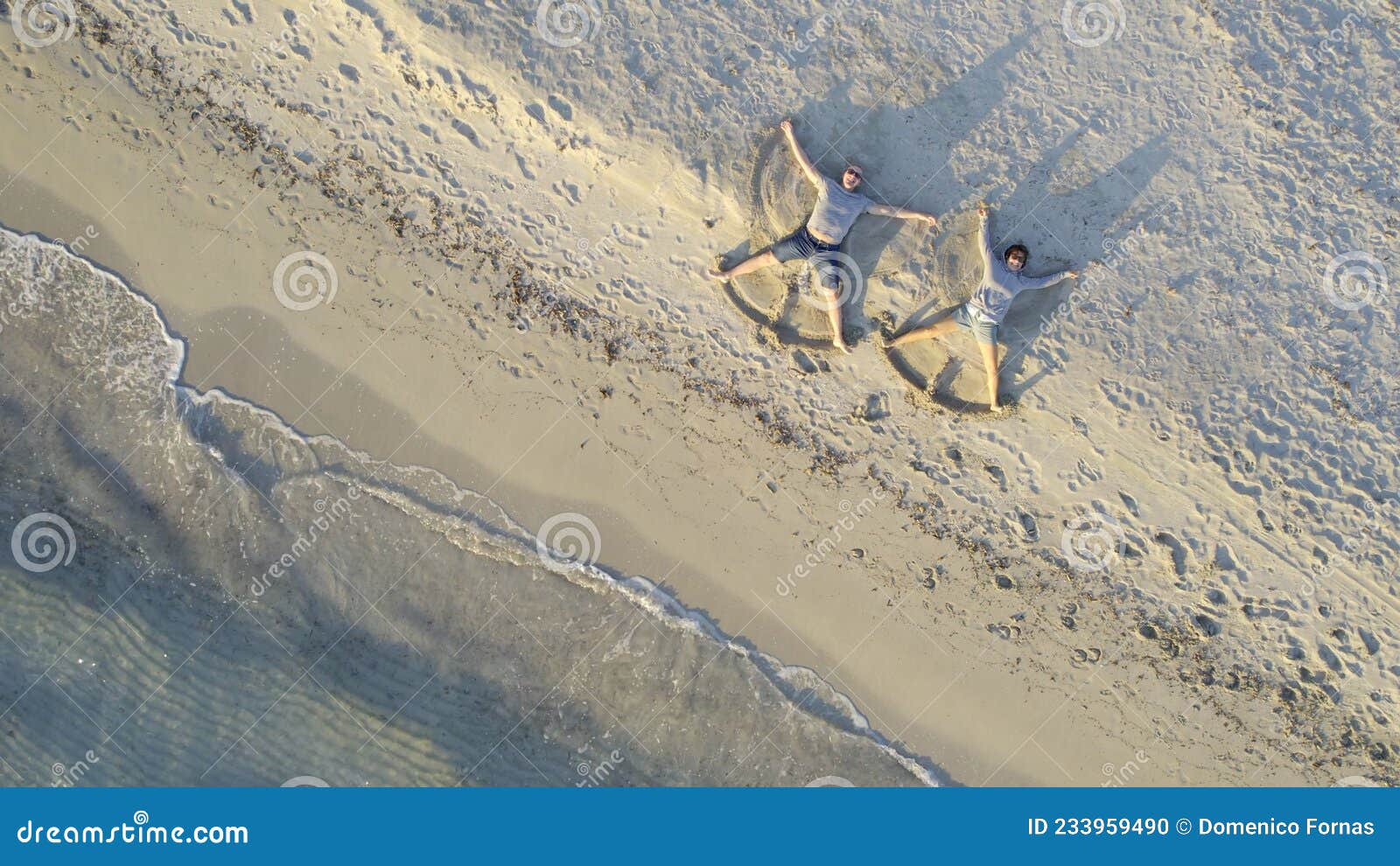 A Couple Making Angels on the Sand at Sunset, Aerial Stock Photo ...