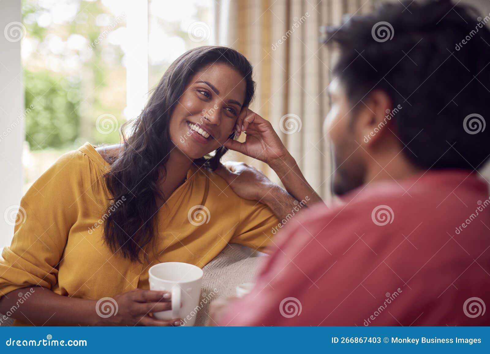 Couple Relaxing On Sofa At Home Together With Hot Drinks Stock Image