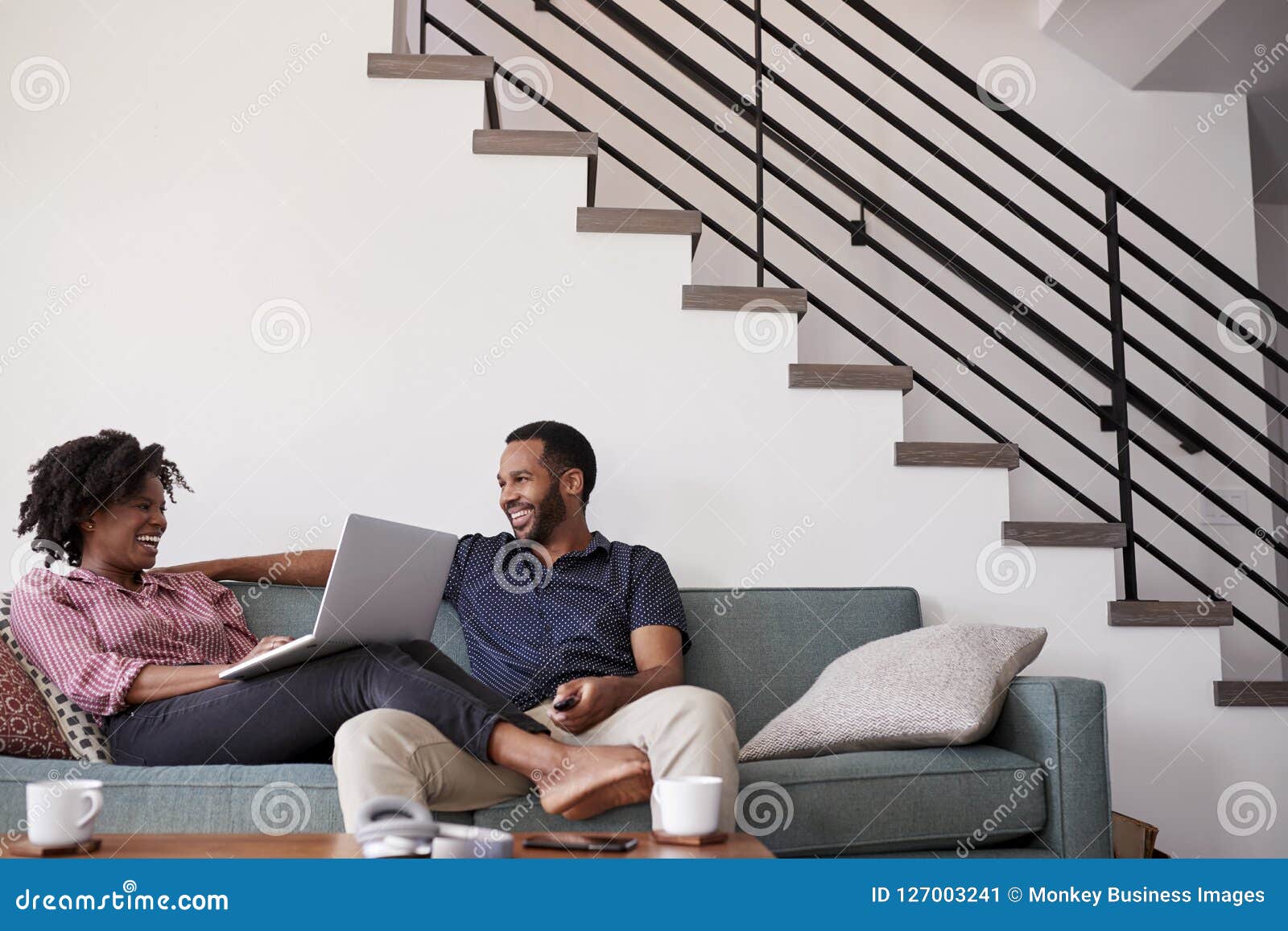 Couple Sitting on Sofa at Home with Woman Using Laptop Computer Stock ...