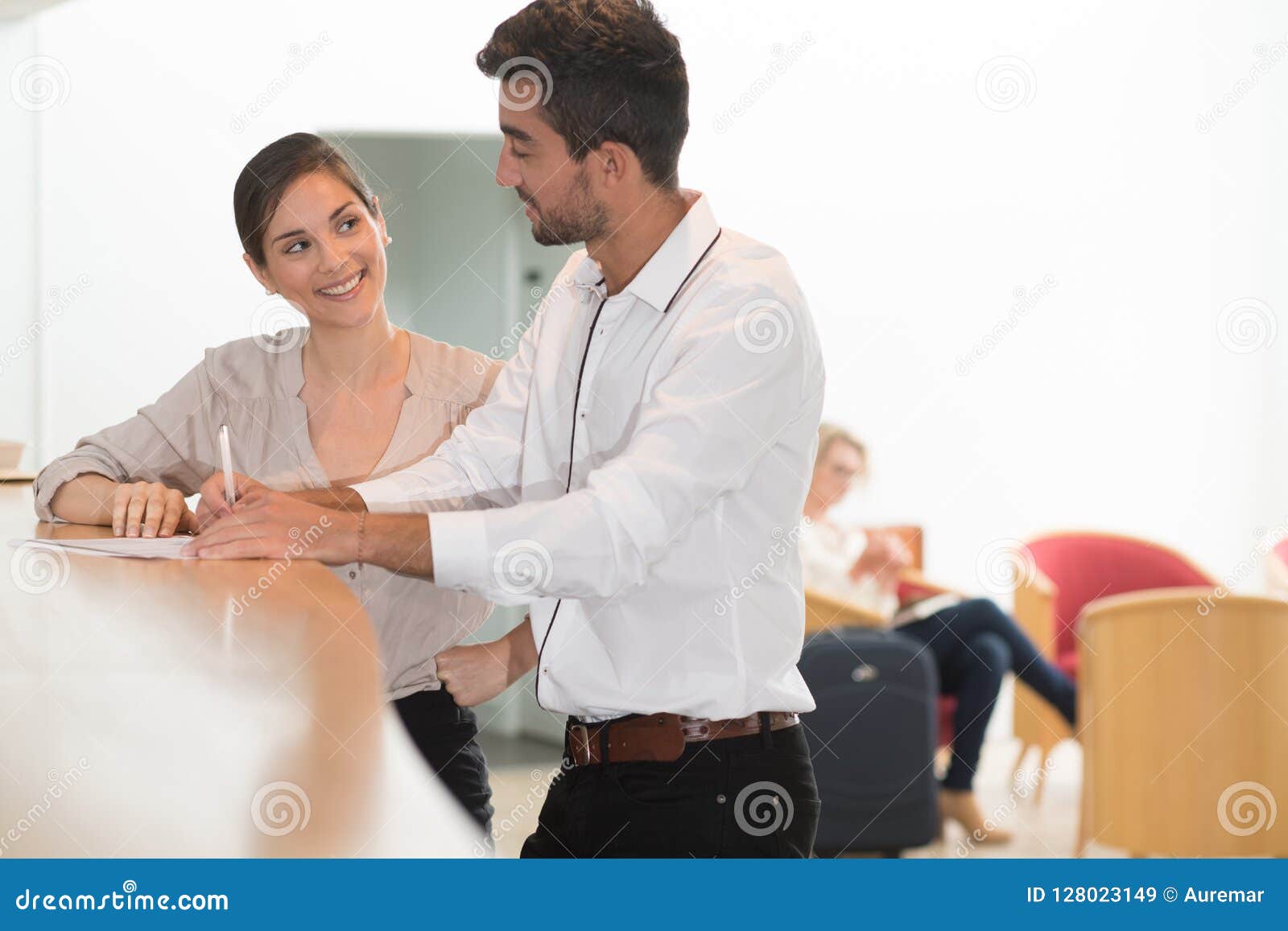 Couple Stood at Reception Desk Filling in Papers Stock Image - Image of ...